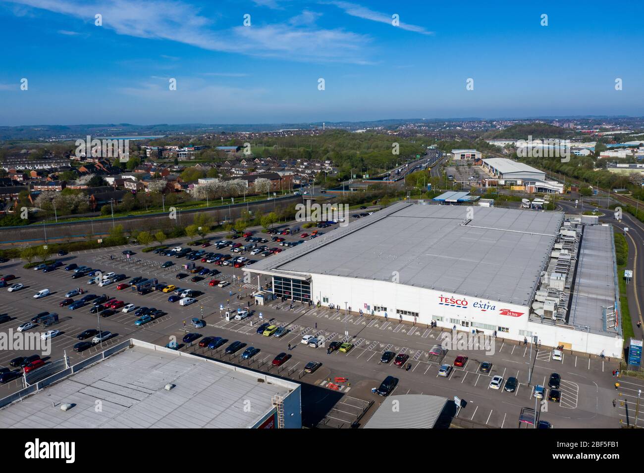 People queue 2 metres apart for a long distance outside of the Tesco ...