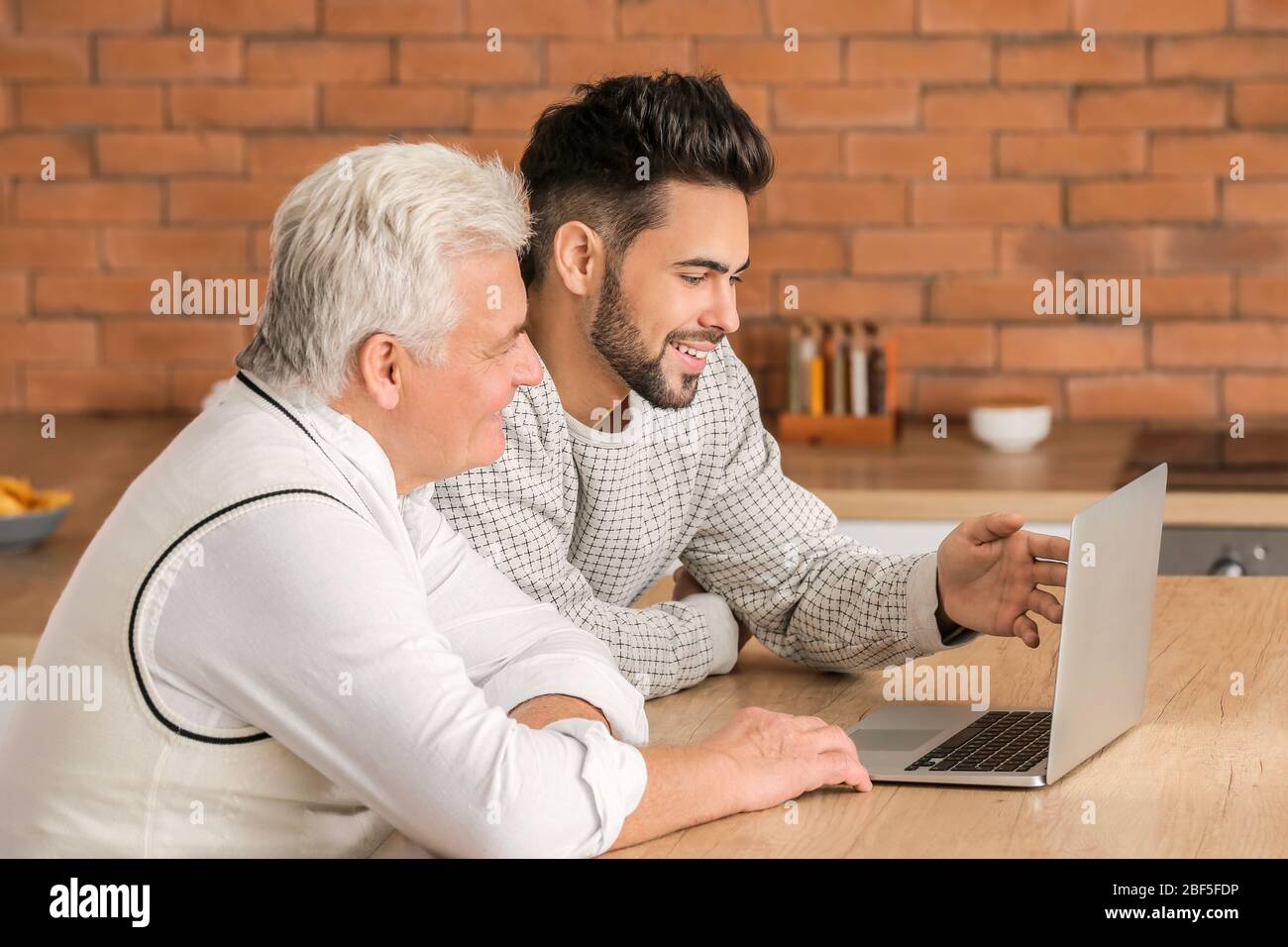 Young man and his father with laptop in kitchen Stock Photo - Alamy