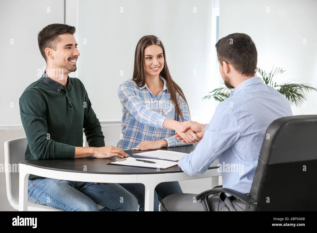 Bank manager shaking hands with couple in office Stock Photo - Alamy