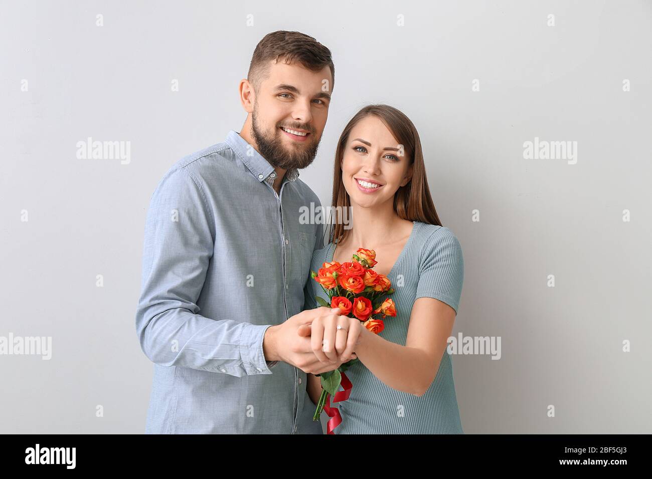 Happy engaged young couple on light background Stock Photo - Alamy