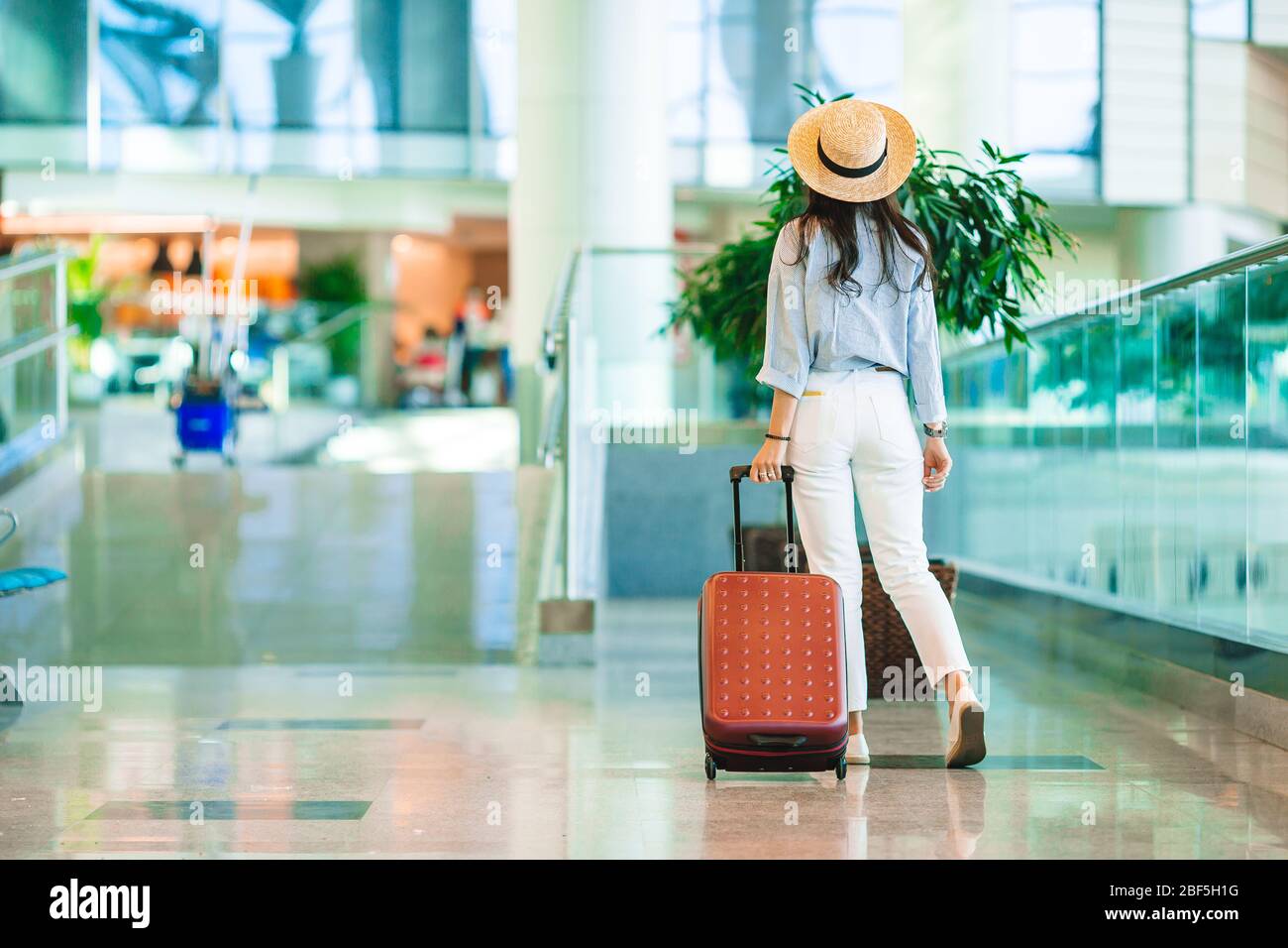 Young woman in hat with baggage in international airport walking with ...
