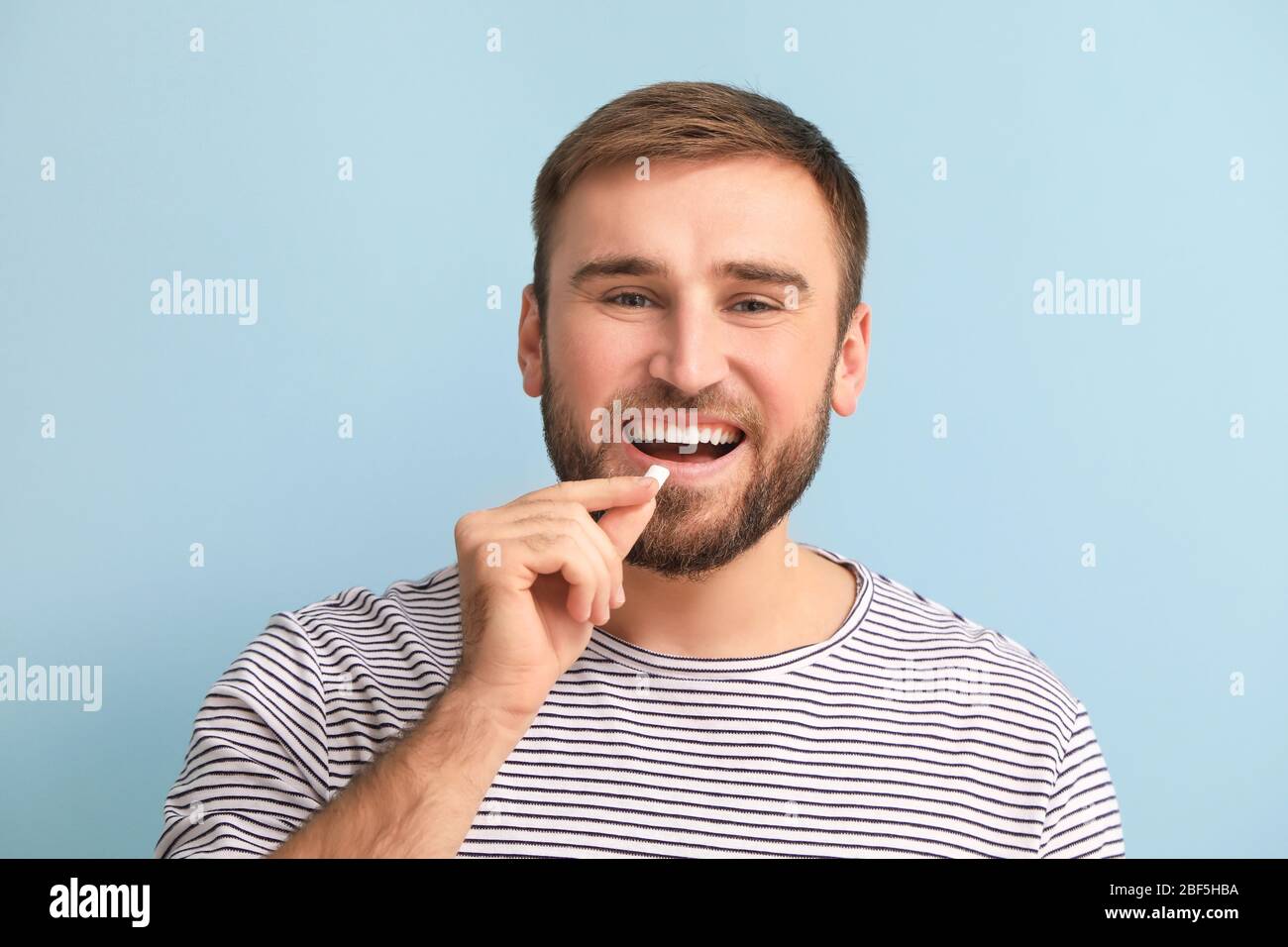 Young man with chewing gum on color background Stock Photo - Alamy