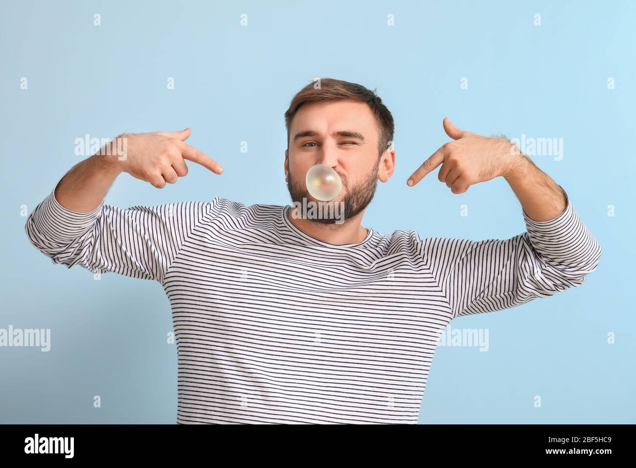 Funny man with chewing gum on color background Stock Photo - Alamy