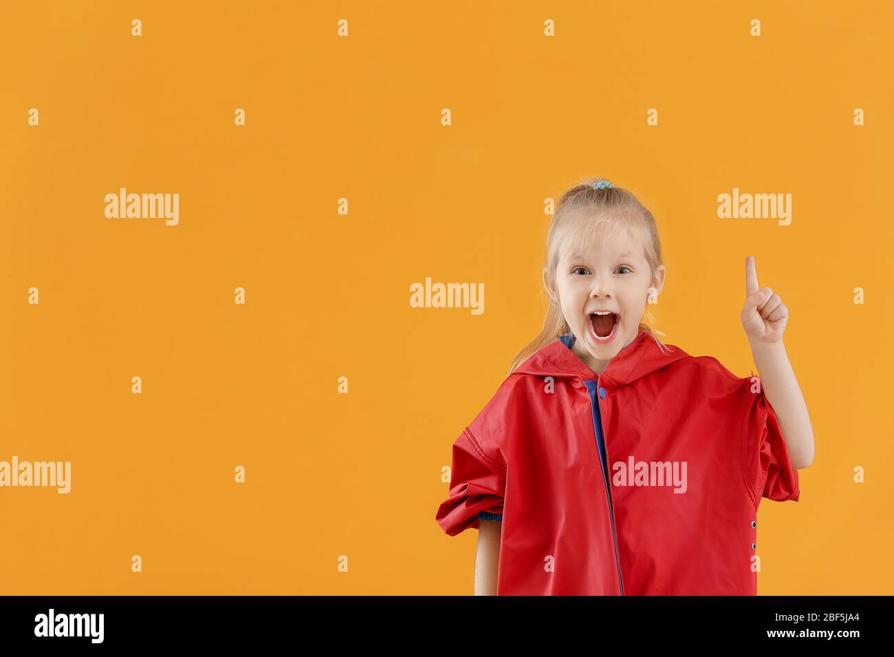 Cute little girl with raised index finger on color background Stock ...