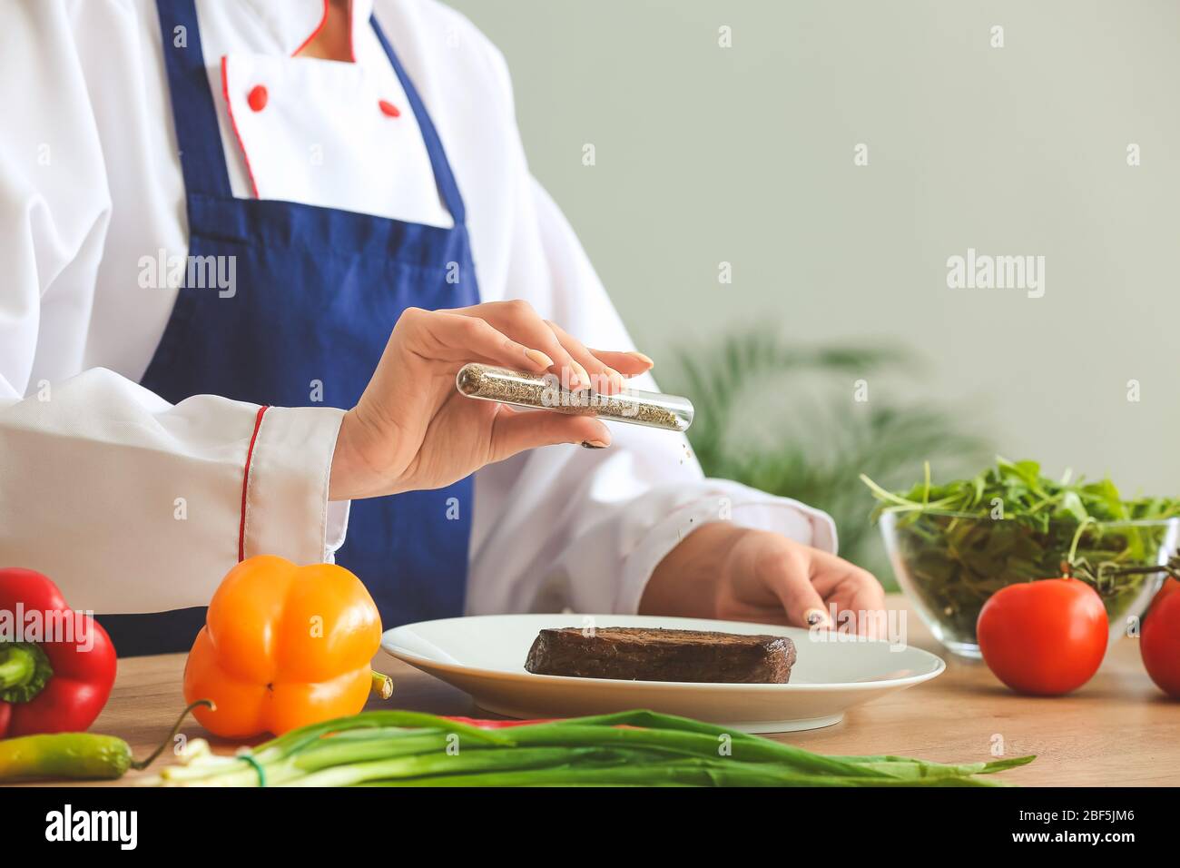 Female chef adding spices to tasty meat in kitchen Stock Photo - Alamy