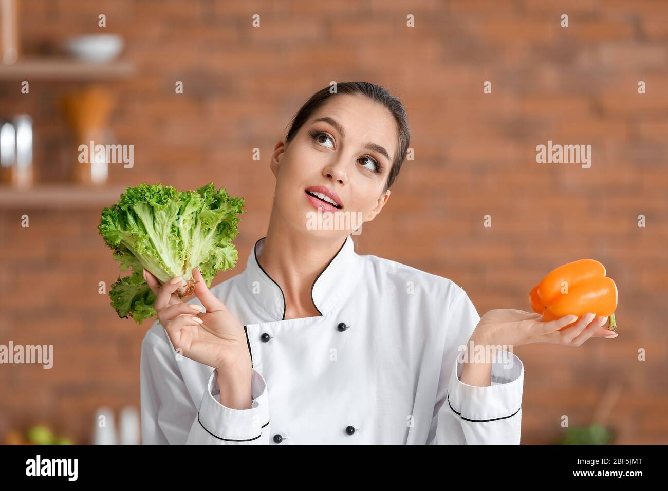 Beautiful female chef with vegetables in kitchen Stock Photo - Alamy