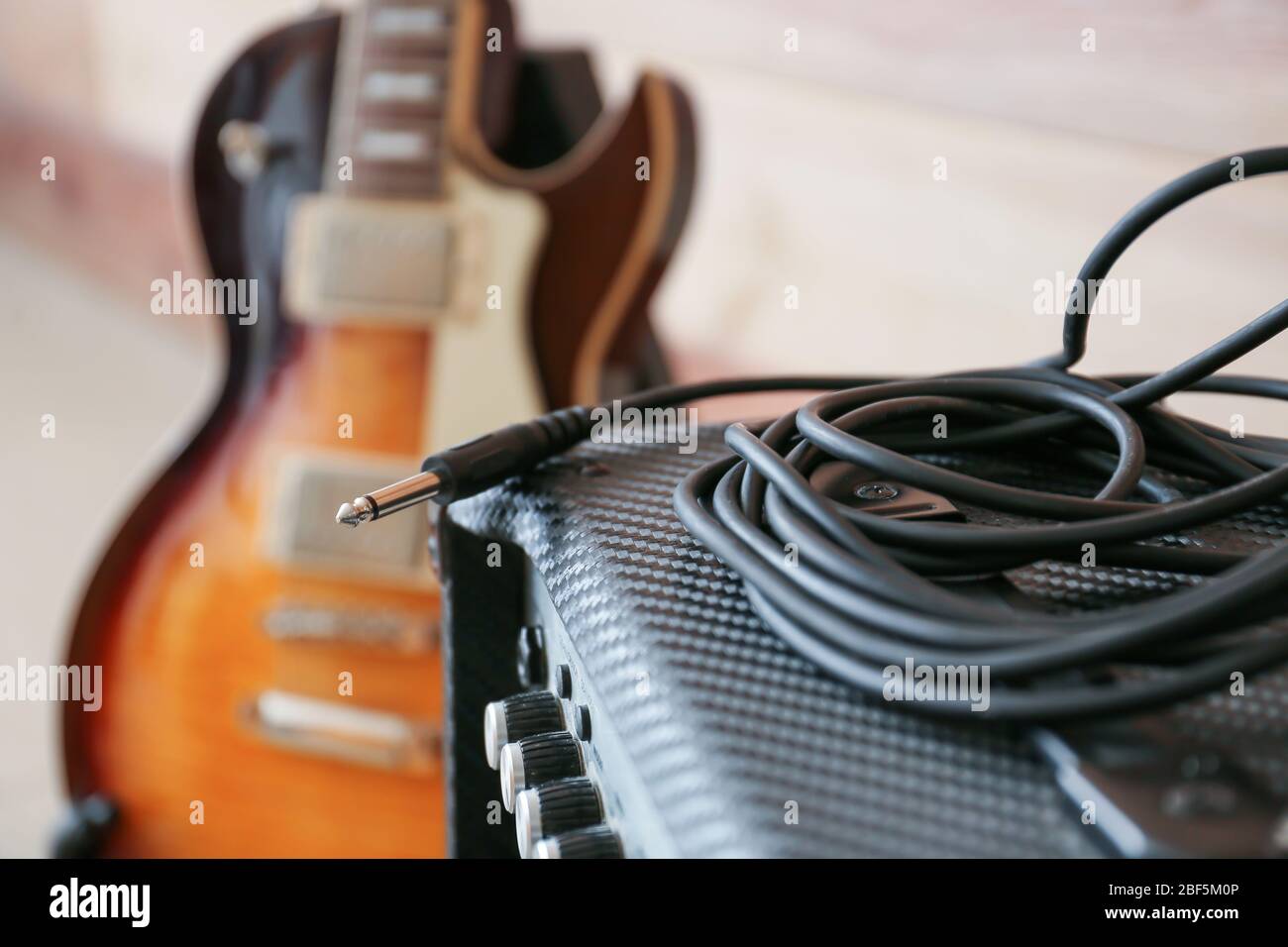 Modern amplifier and guitar near wooden wall, closeup Stock Photo - Alamy