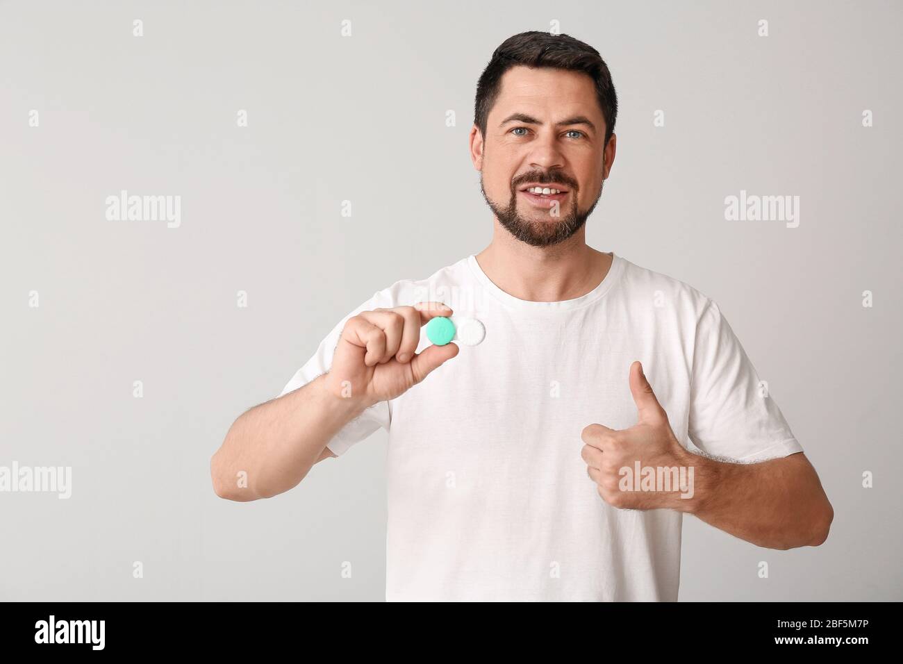 Man with contact lenses showing thumb-up on light background Stock ...