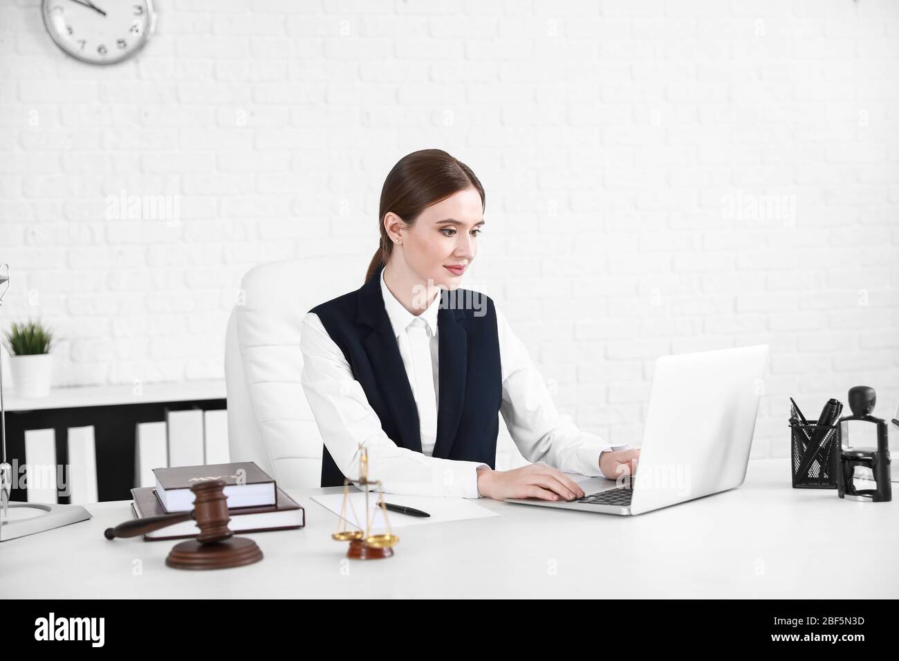 Female lawyer with laptop sitting at workplace in office Stock Photo ...