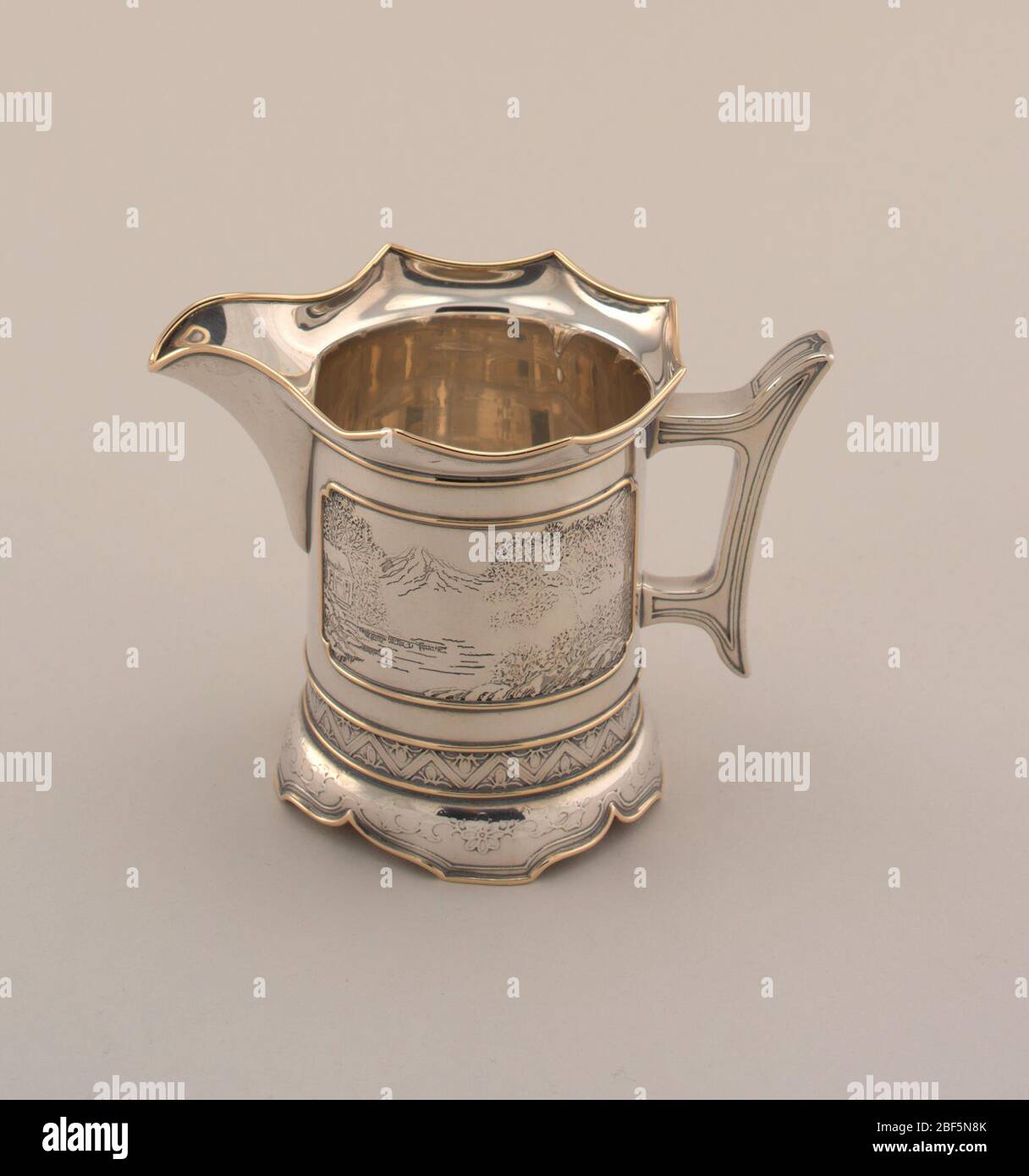 Cream jug. Cylindrical form with applied gold edges and chased with ...