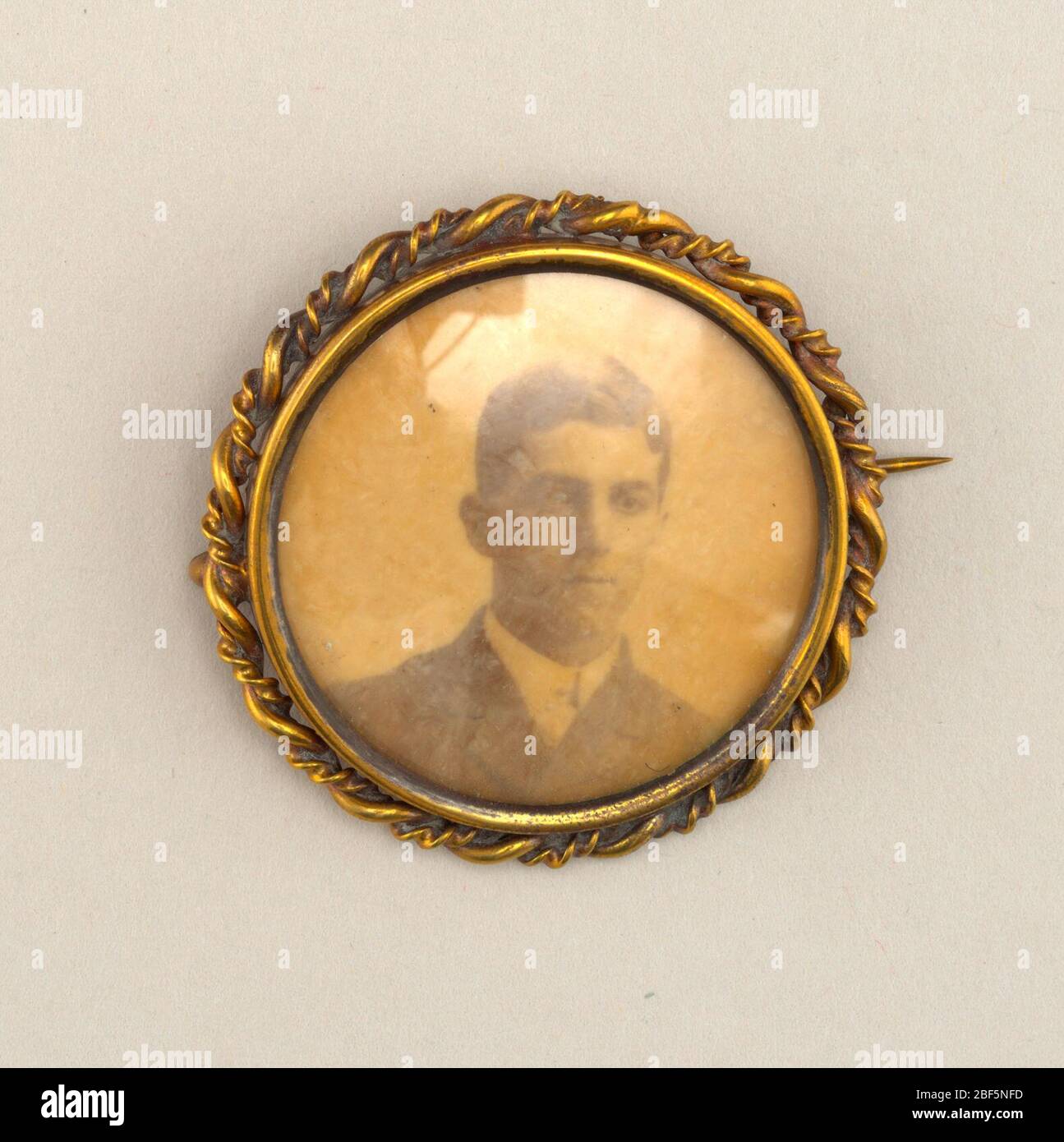 Brooch. Circular; portrait of a young man; gilded metal frame with ...