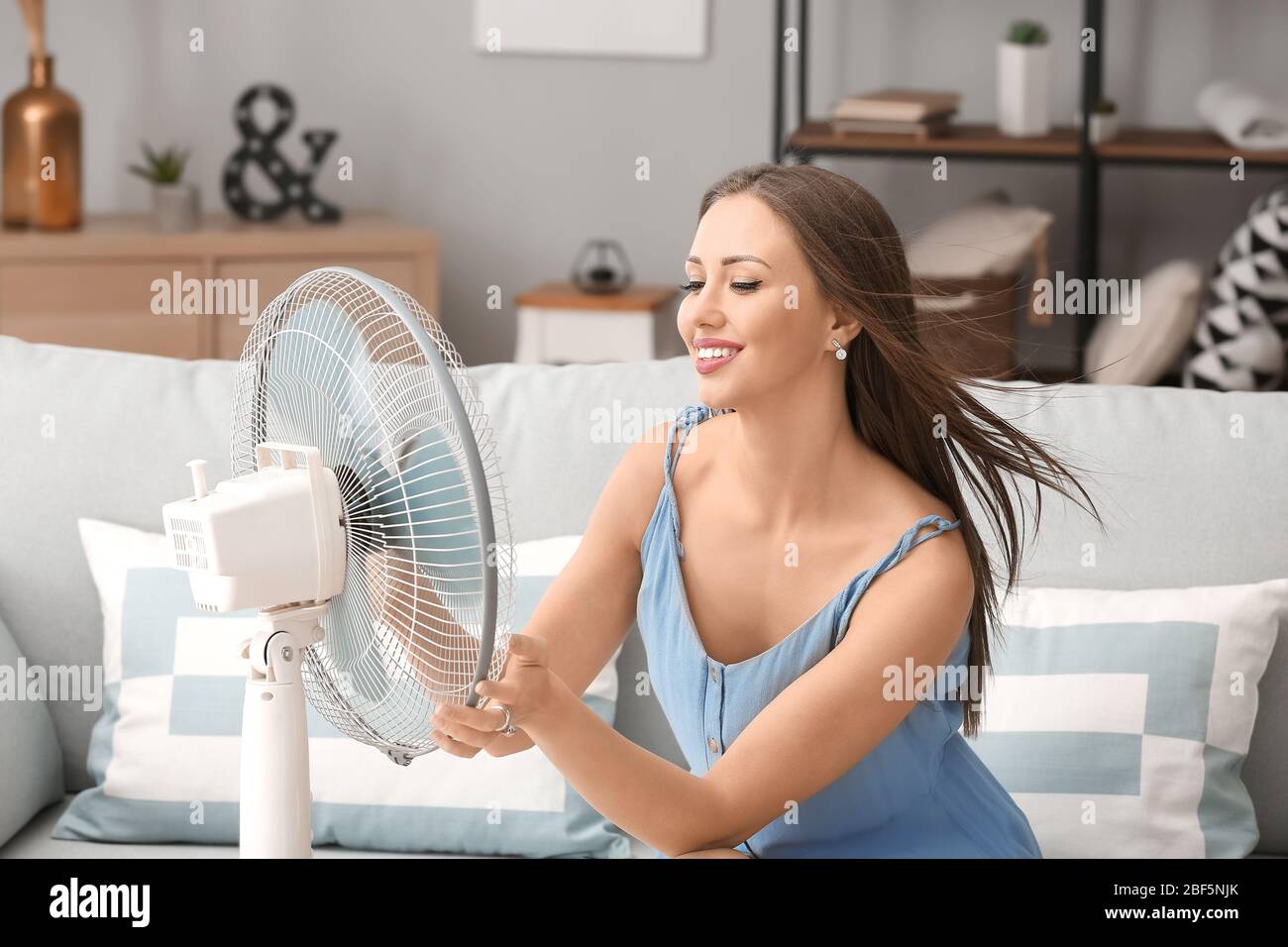 Young woman using electric fan during heatwave at home Stock Photo - Alamy