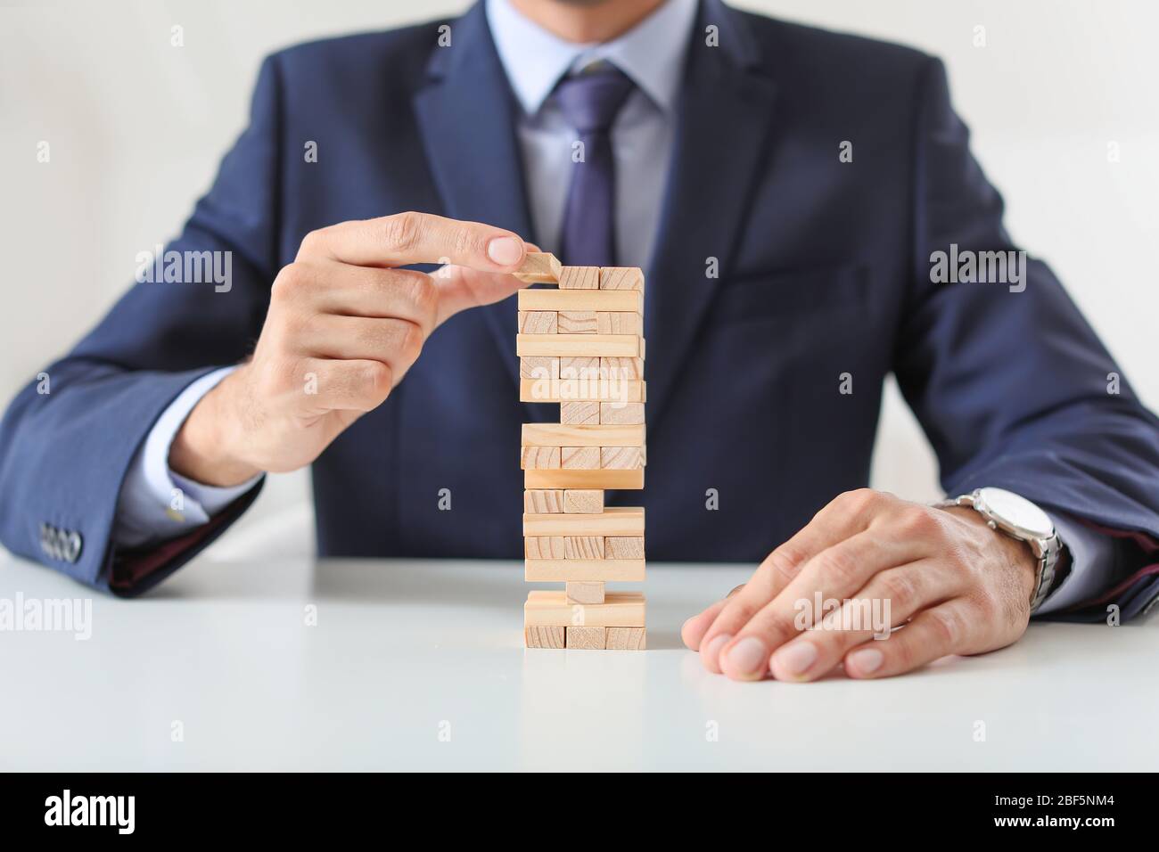 Businessman manager building tower from blocks at table. Concept of ...