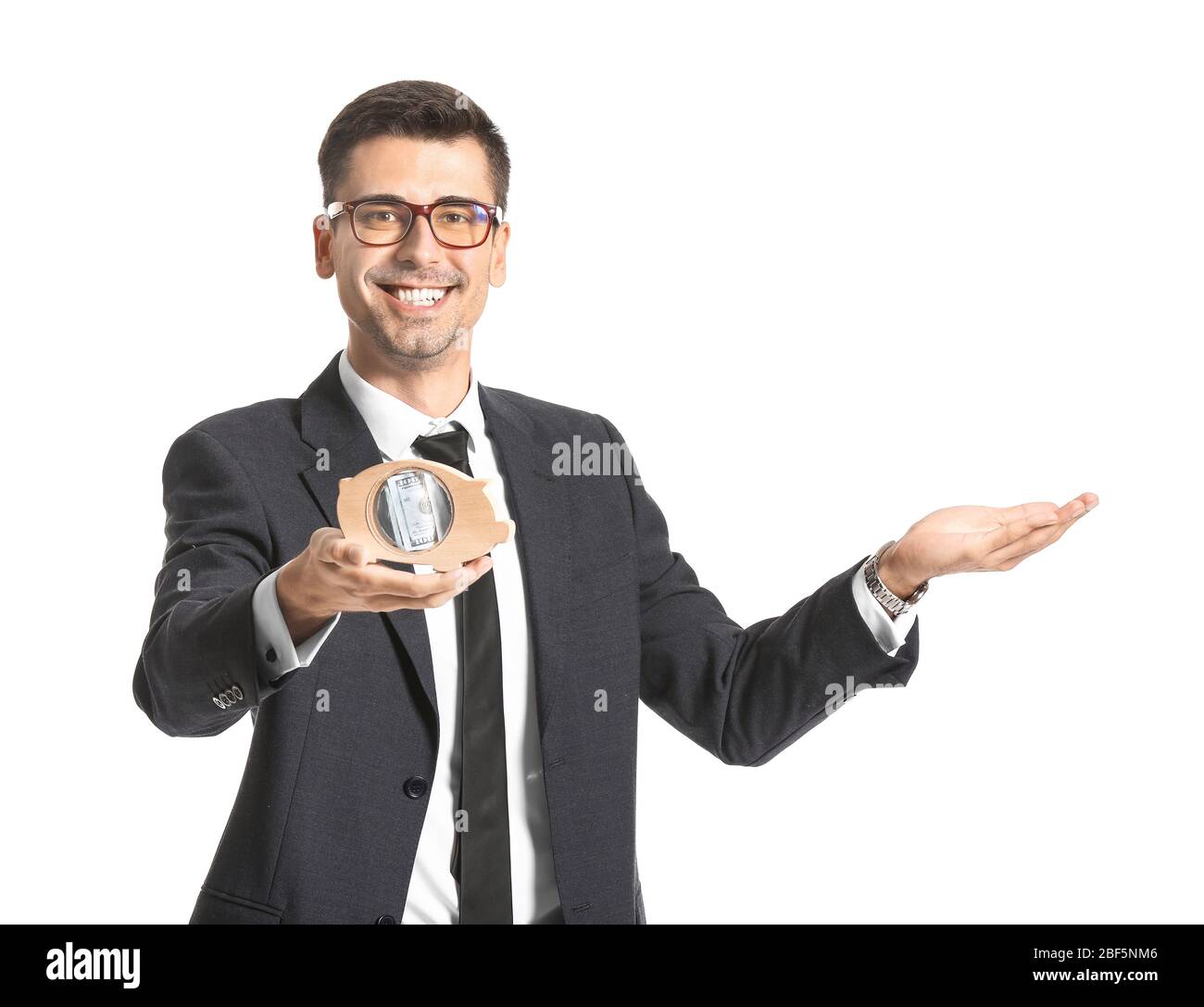 Happy male bank manager with piggy bank showing something on white ...