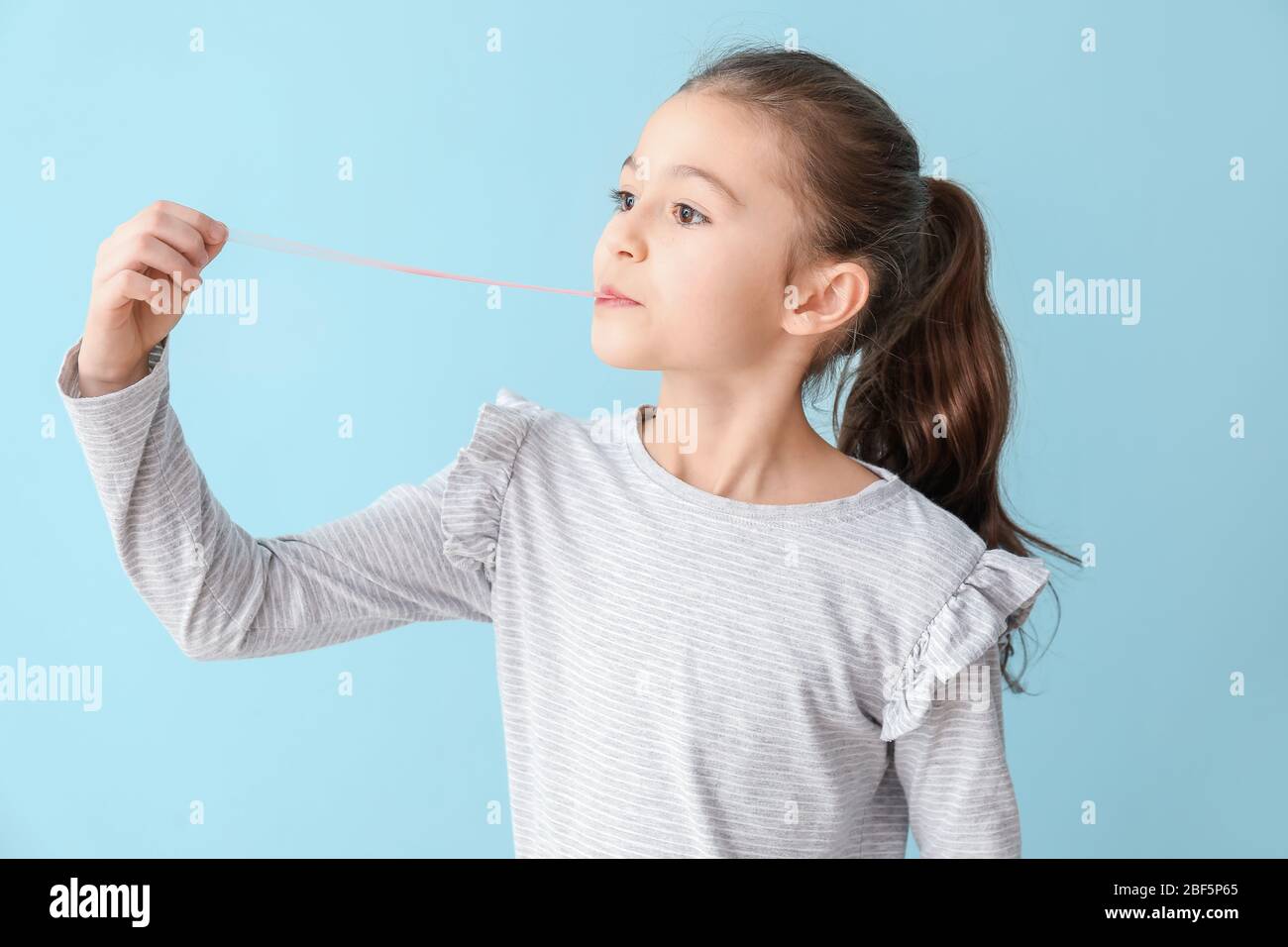 Cute little girl with chewing gum on color background Stock Photo - Alamy