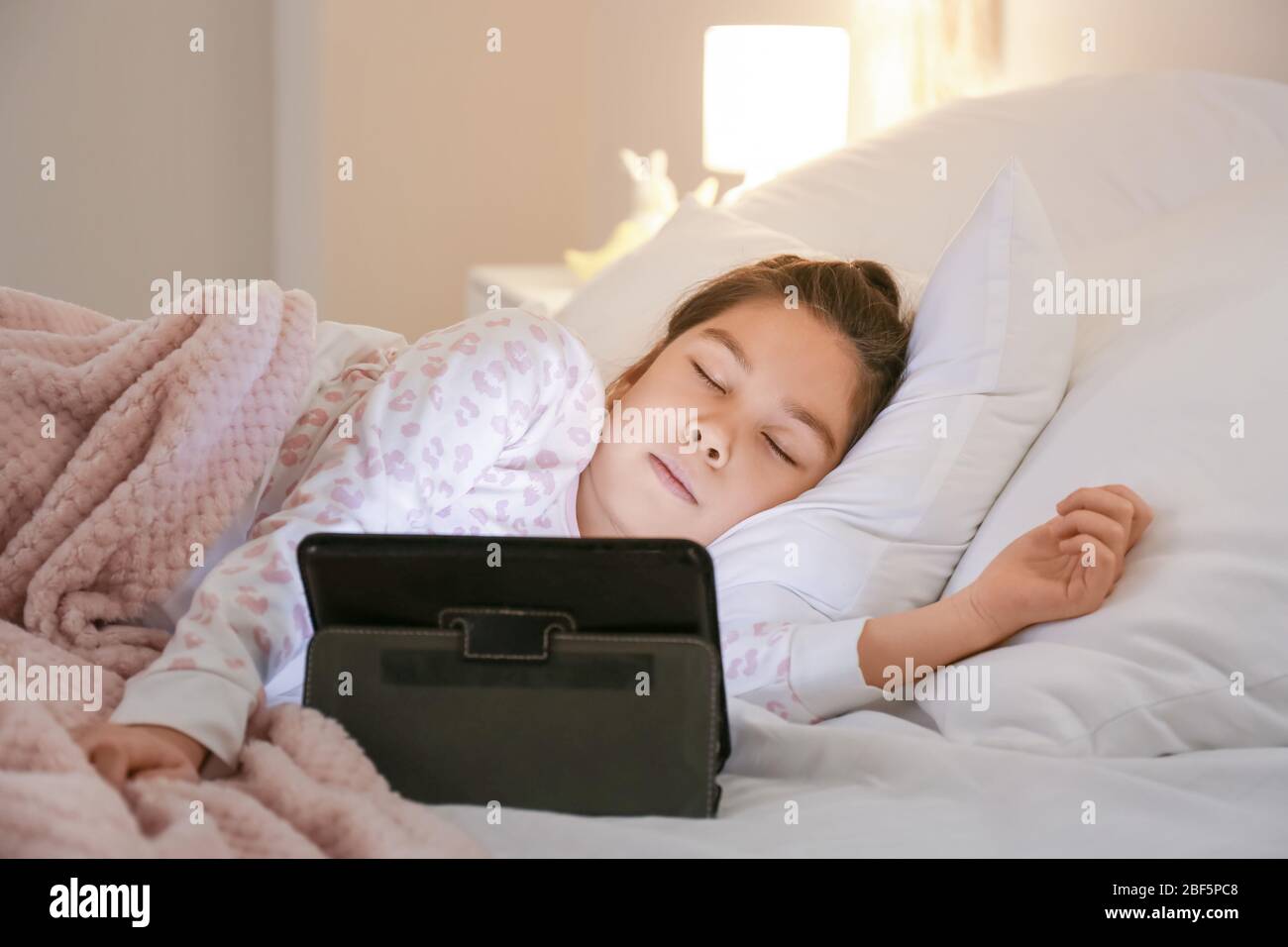 Cute little Asian girl sleeping in bed after watching cartoons Stock ...