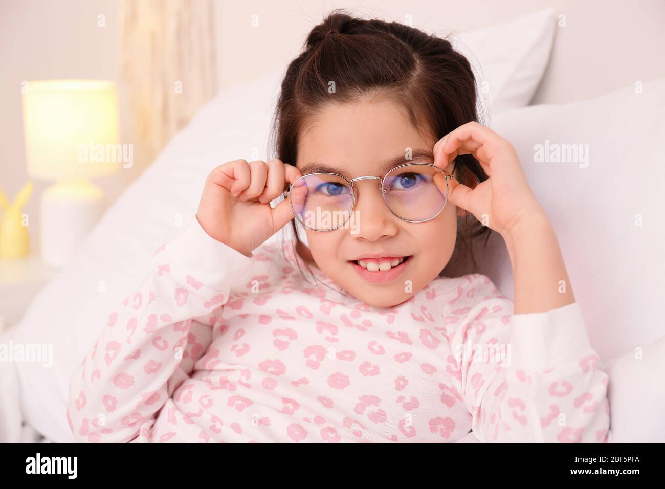 Cute little girl with glasses in bed Stock Photo - Alamy