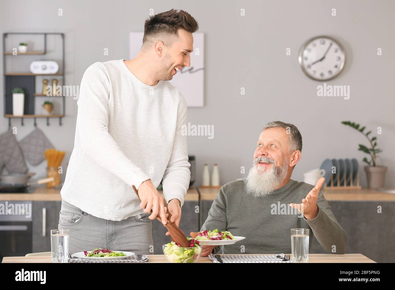 Senior man and his adult son having dinner in kitchen Stock Photo - Alamy