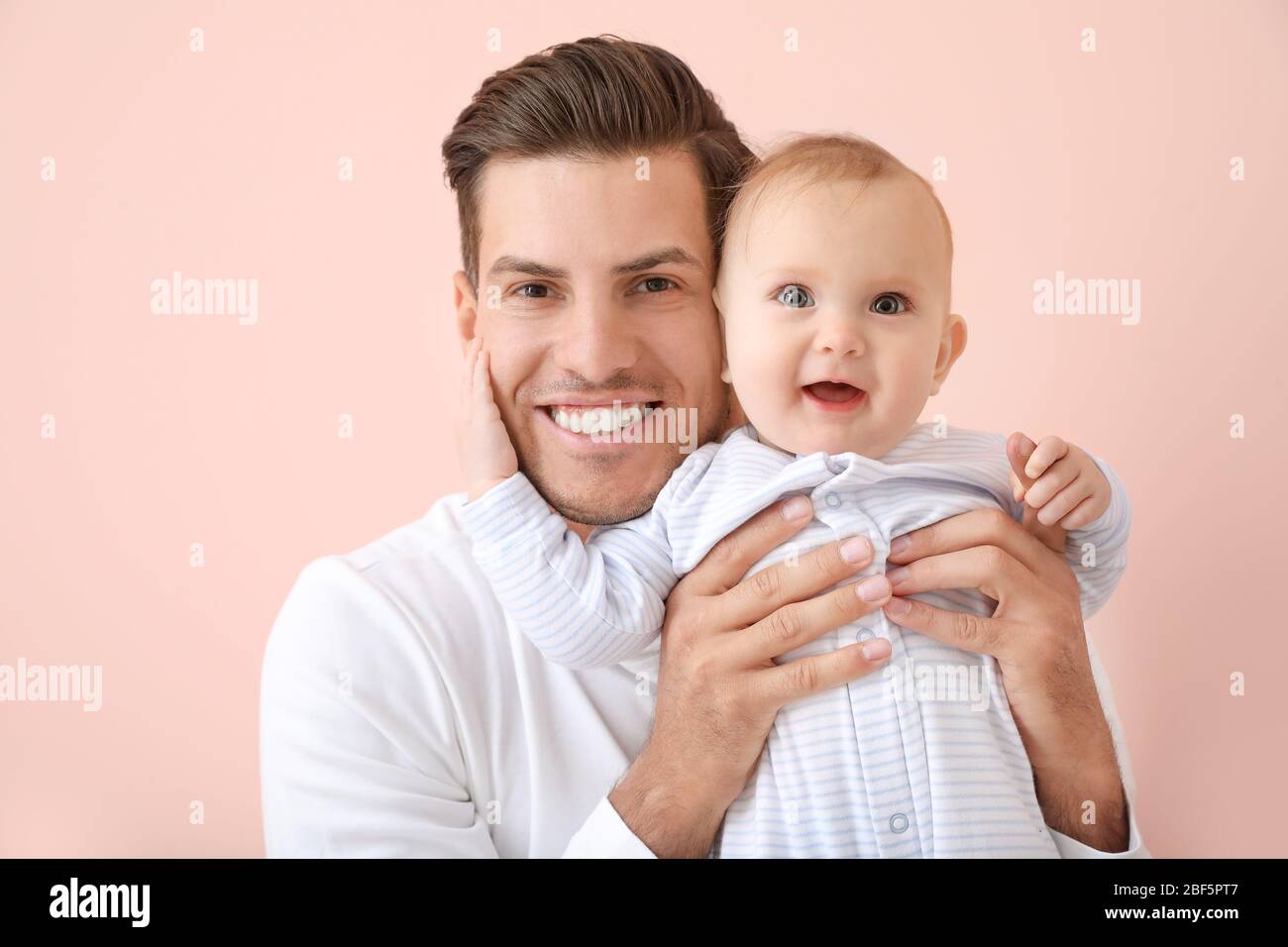 Cute baby with father on color background Stock Photo - Alamy