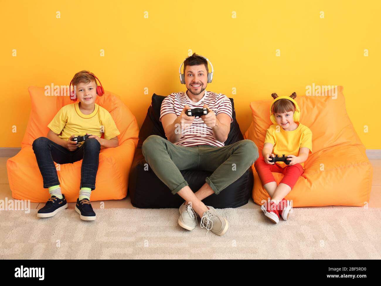 Father and his little children playing video games at home Stock Photo ...