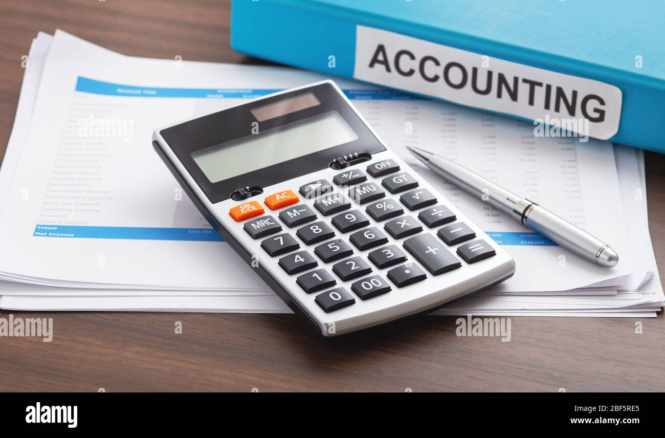 Calculator with accounting report and pen on wooden office desk ...