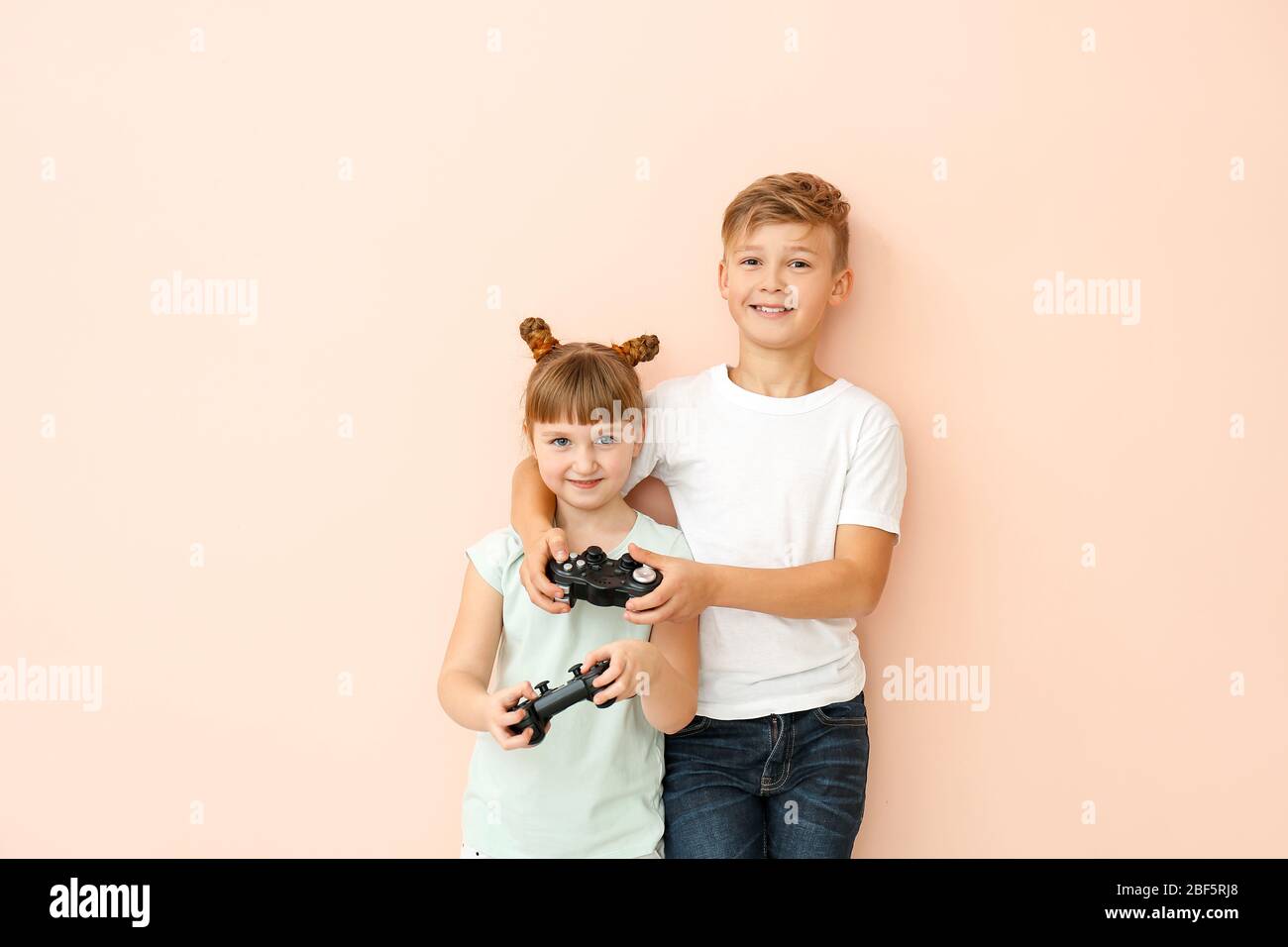 Little children playing video games on color background Stock Photo - Alamy