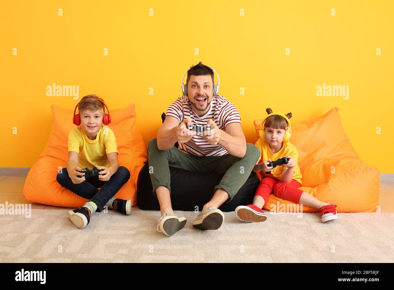 Father and his little children playing video games at home Stock Photo ...
