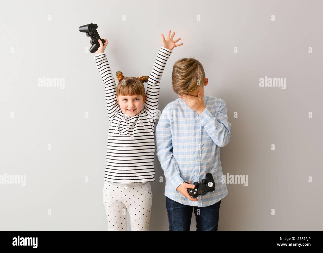 Little children playing video games on grey background Stock Photo - Alamy