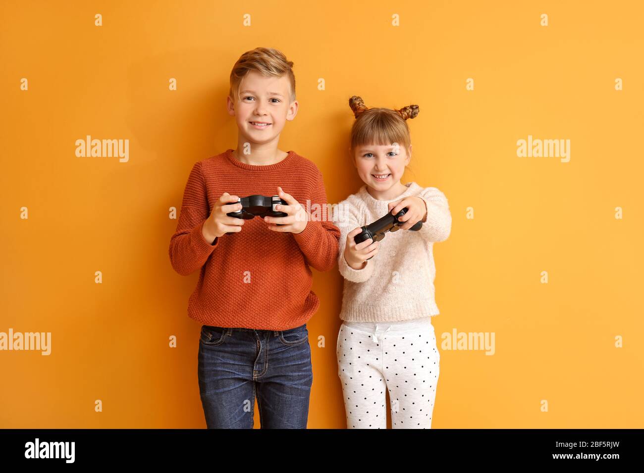 Little children playing video games on color background Stock Photo - Alamy