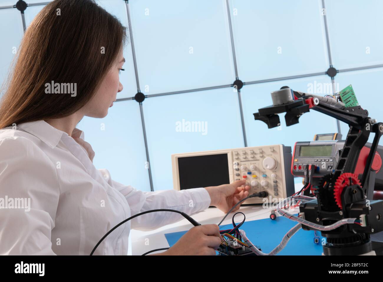 A young woman writes an algorithm for the robot arm. Science Research ...