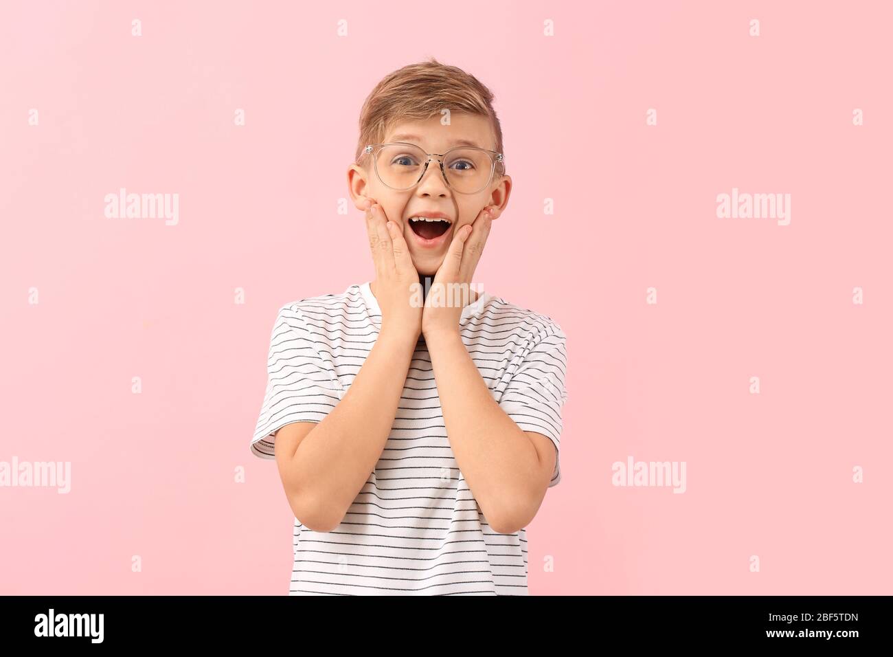 Surprised little boy with eyeglasses on color background Stock Photo ...