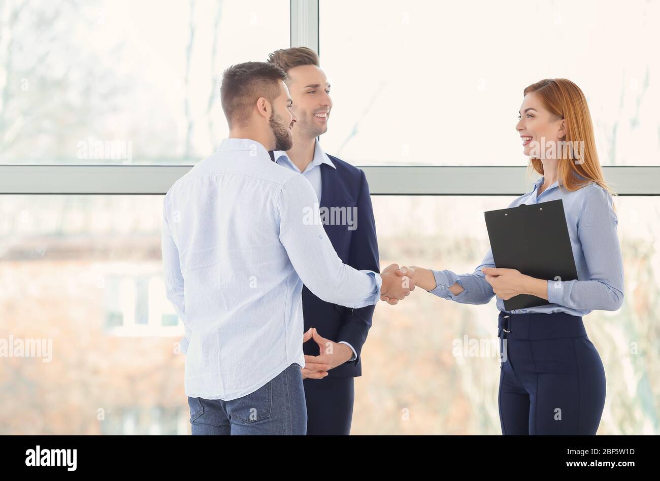 Bank manager and clients shaking hands in office Stock Photo - Alamy