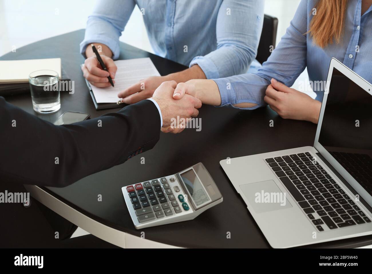 Bank manager and clients shaking hands in office Stock Photo - Alamy