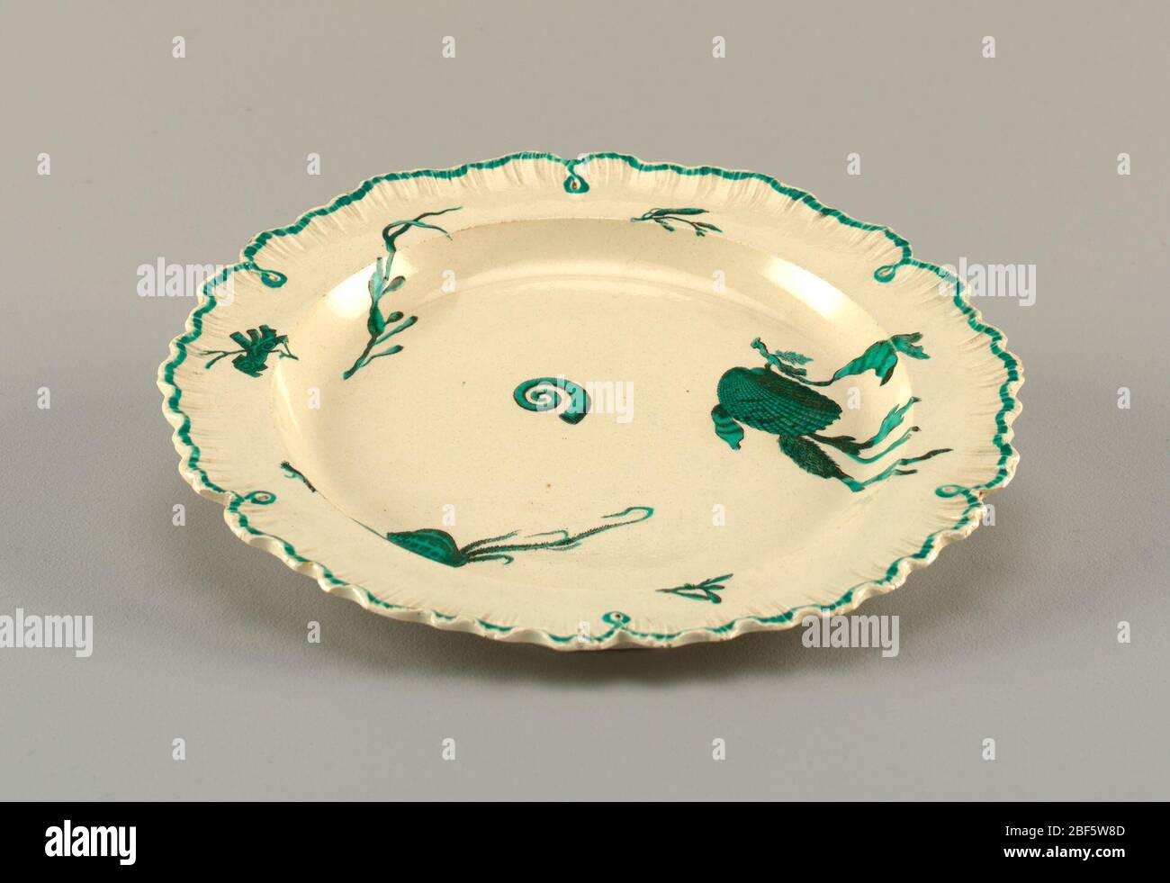 Plate. Round plate with scalloped edges that resemble a shell. Green ...