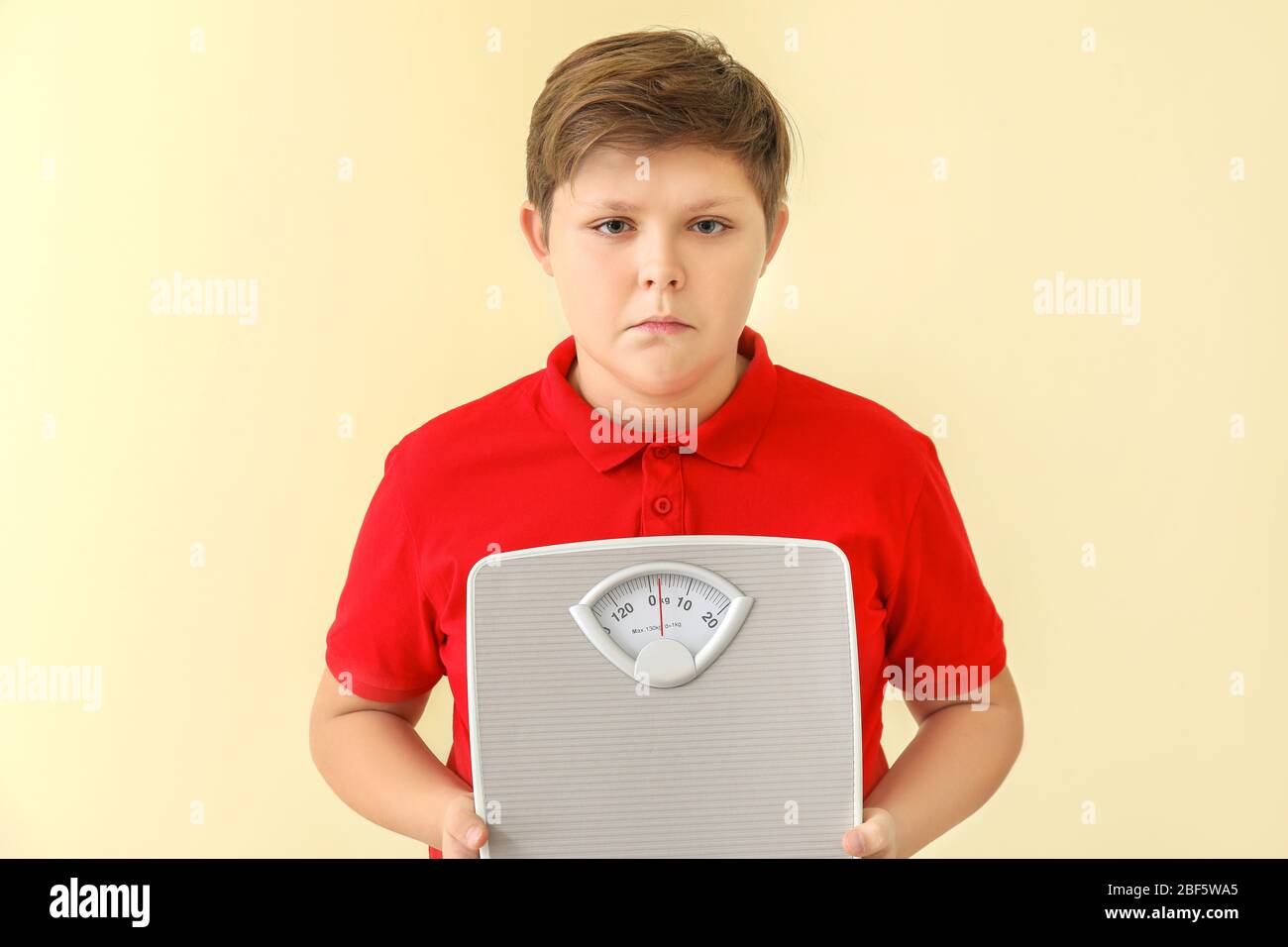 Overweight boy with scales on light background Stock Photo - Alamy