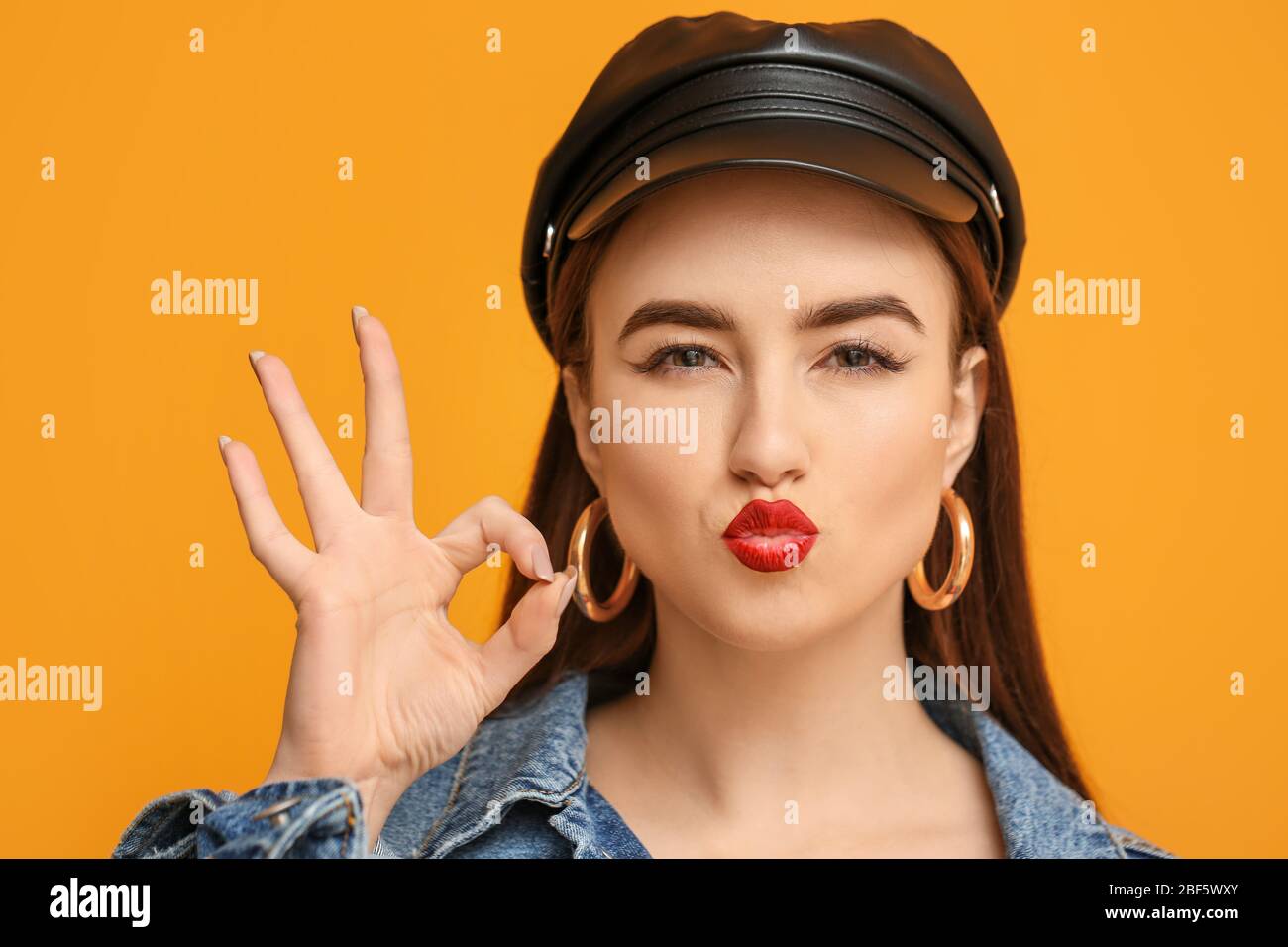 Emotional young woman showing OK gesture on color background Stock ...