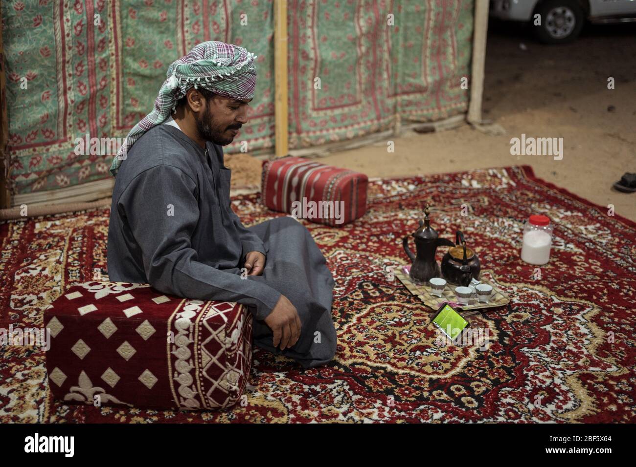 Bedouin man wearing traditional clothes watches a footbal match in a ...
