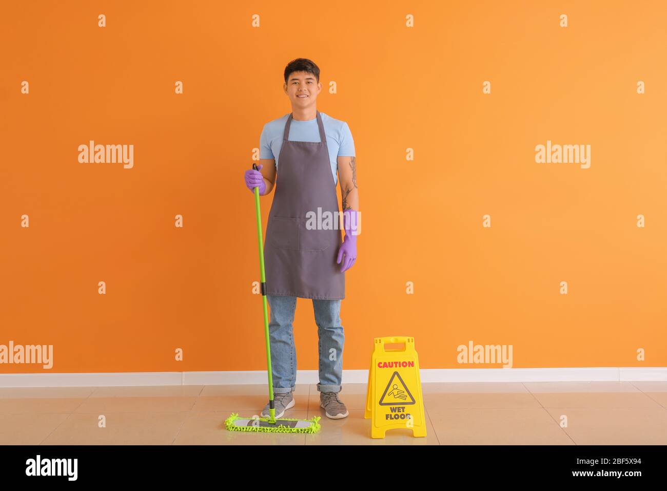 Asian janitor with floor mop near color wall Stock Photo - Alamy
