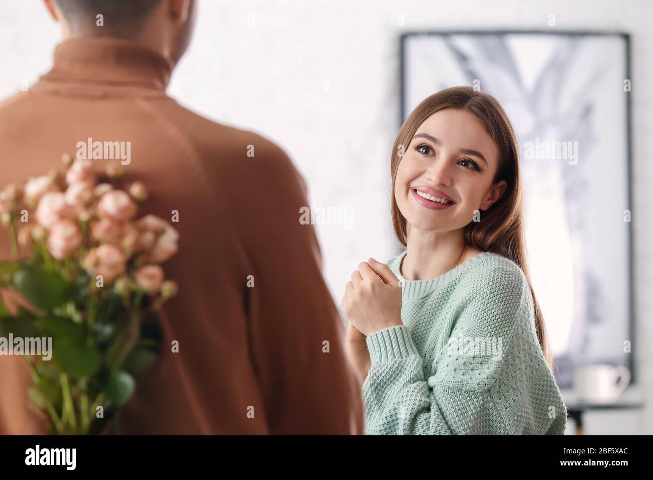 Young man holding behind his back flowers for beautiful girlfriend in ...