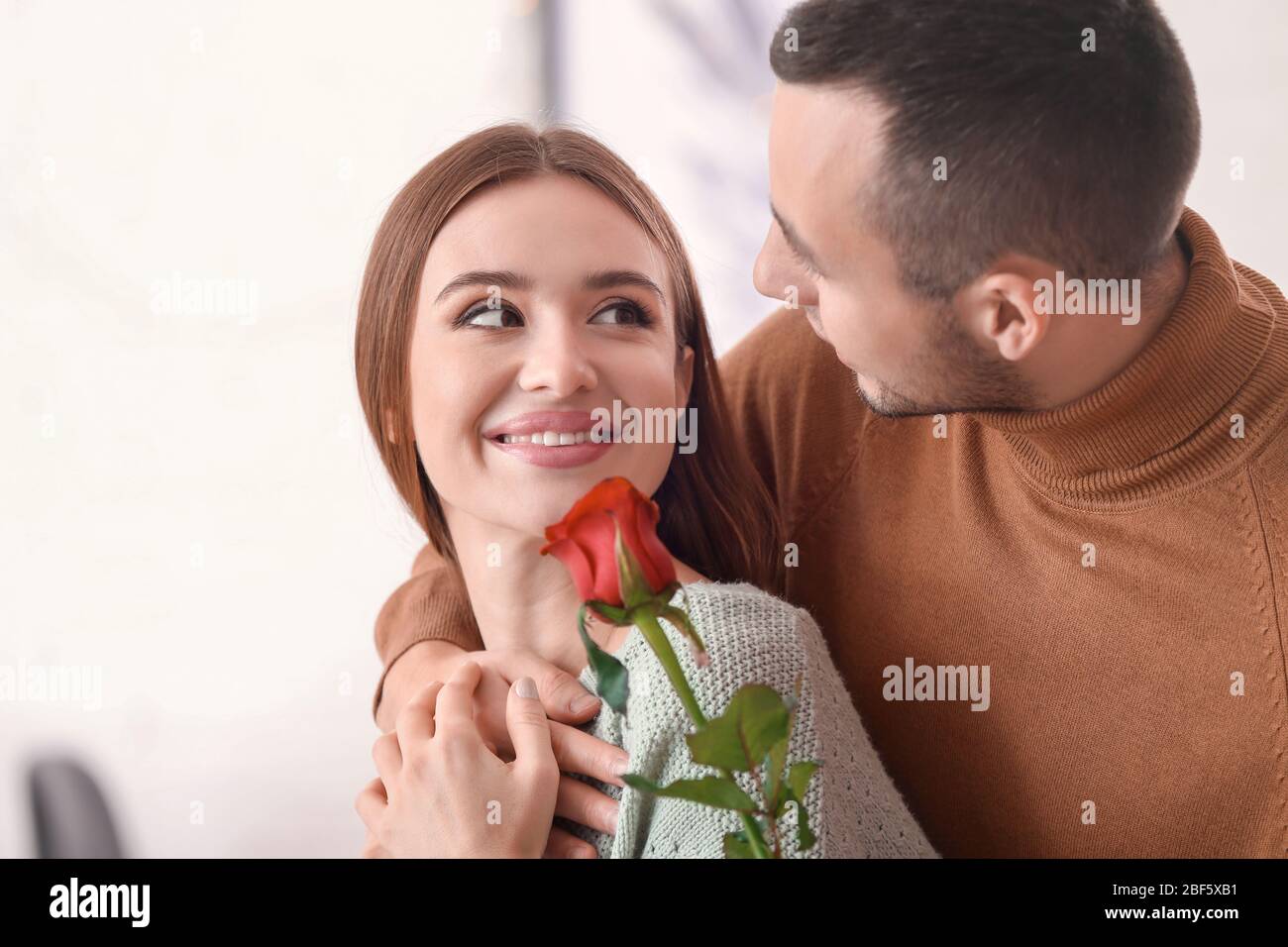 Beautiful young woman receiving flower from her boyfriend on romantic ...