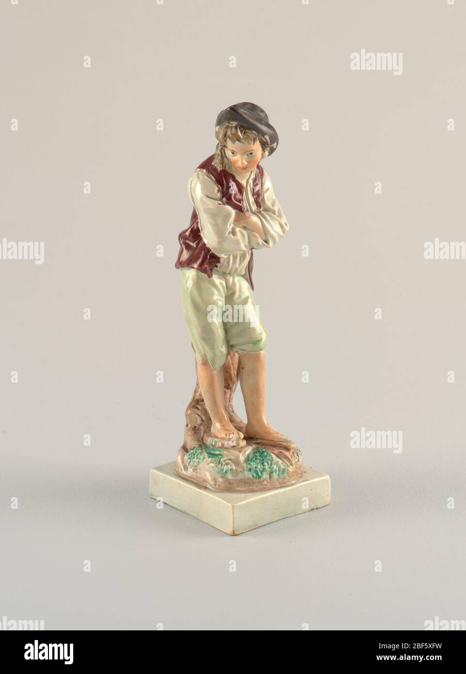 Figure. Standing figure of a boy with folded arms leaning against the ...