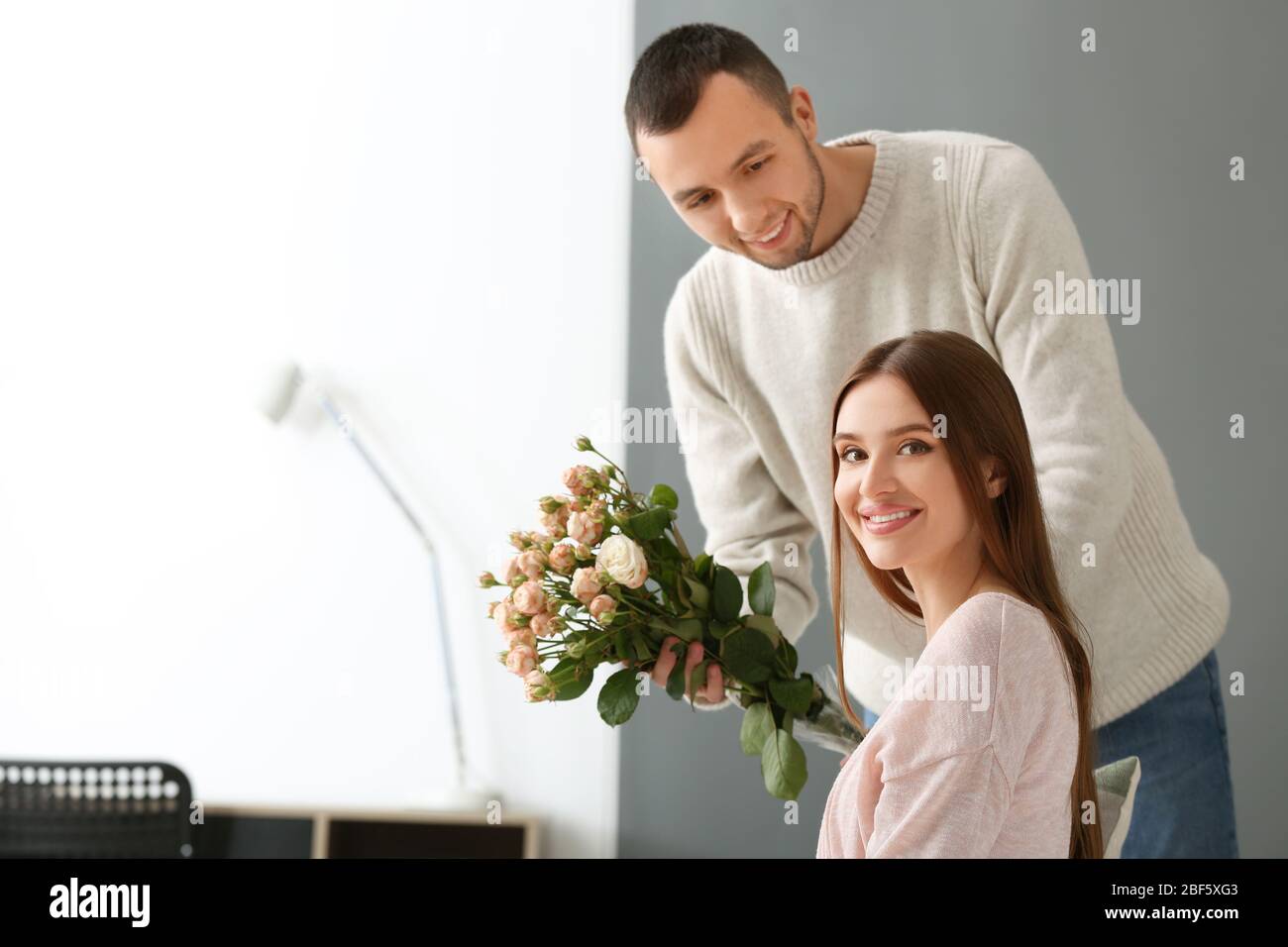 Beautiful young woman receiving flowers from her boyfriend on romantic ...
