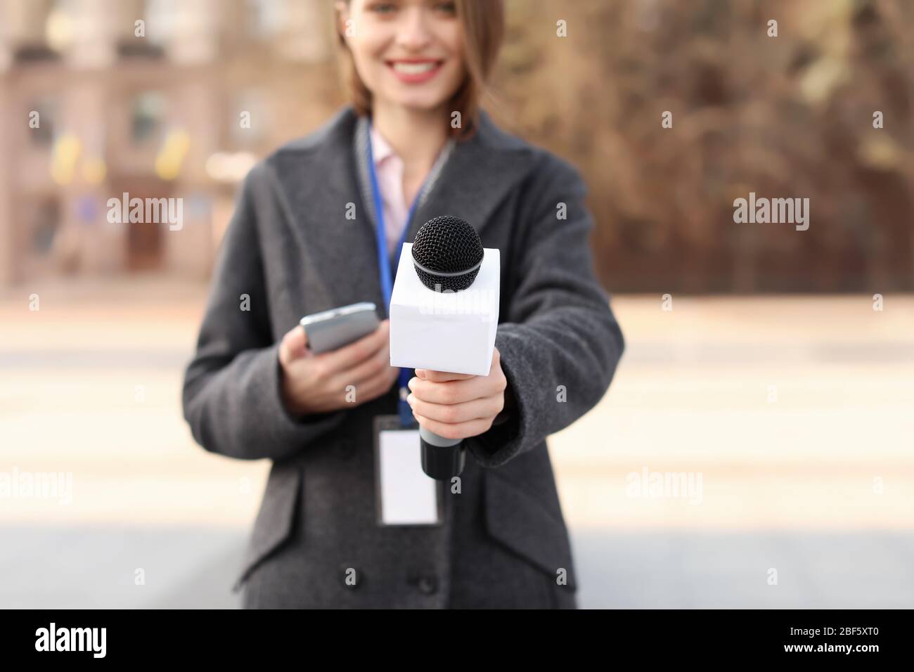 Beautiful journalist with microphone outdoors Stock Photo - Alamy