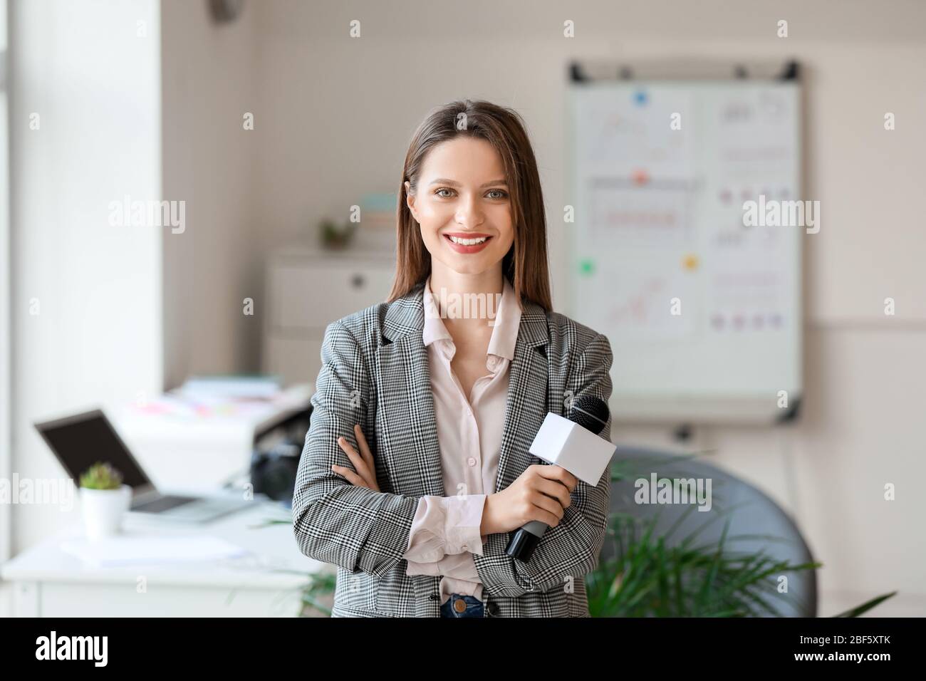 Female journalist with microphone in office Stock Photo - Alamy