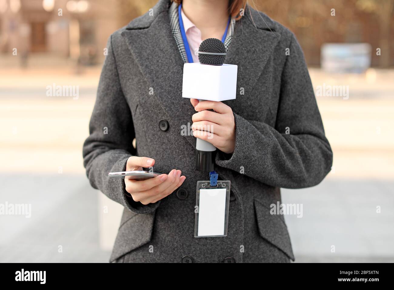 Beautiful journalist with microphone outdoors Stock Photo - Alamy