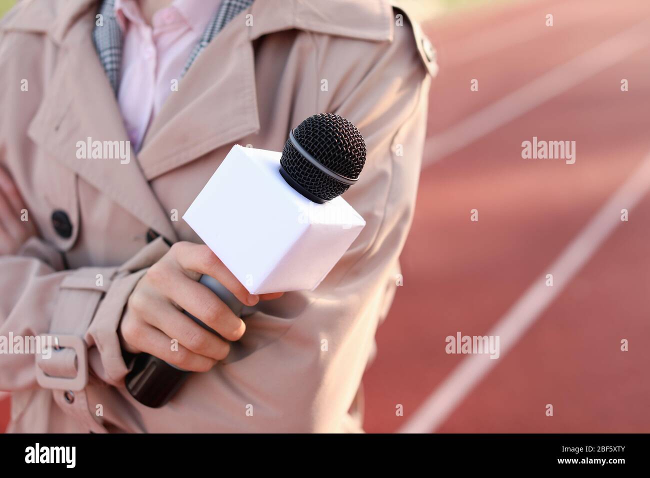 Beautiful reporter with microphone at the stadium, closeup Stock Photo ...
