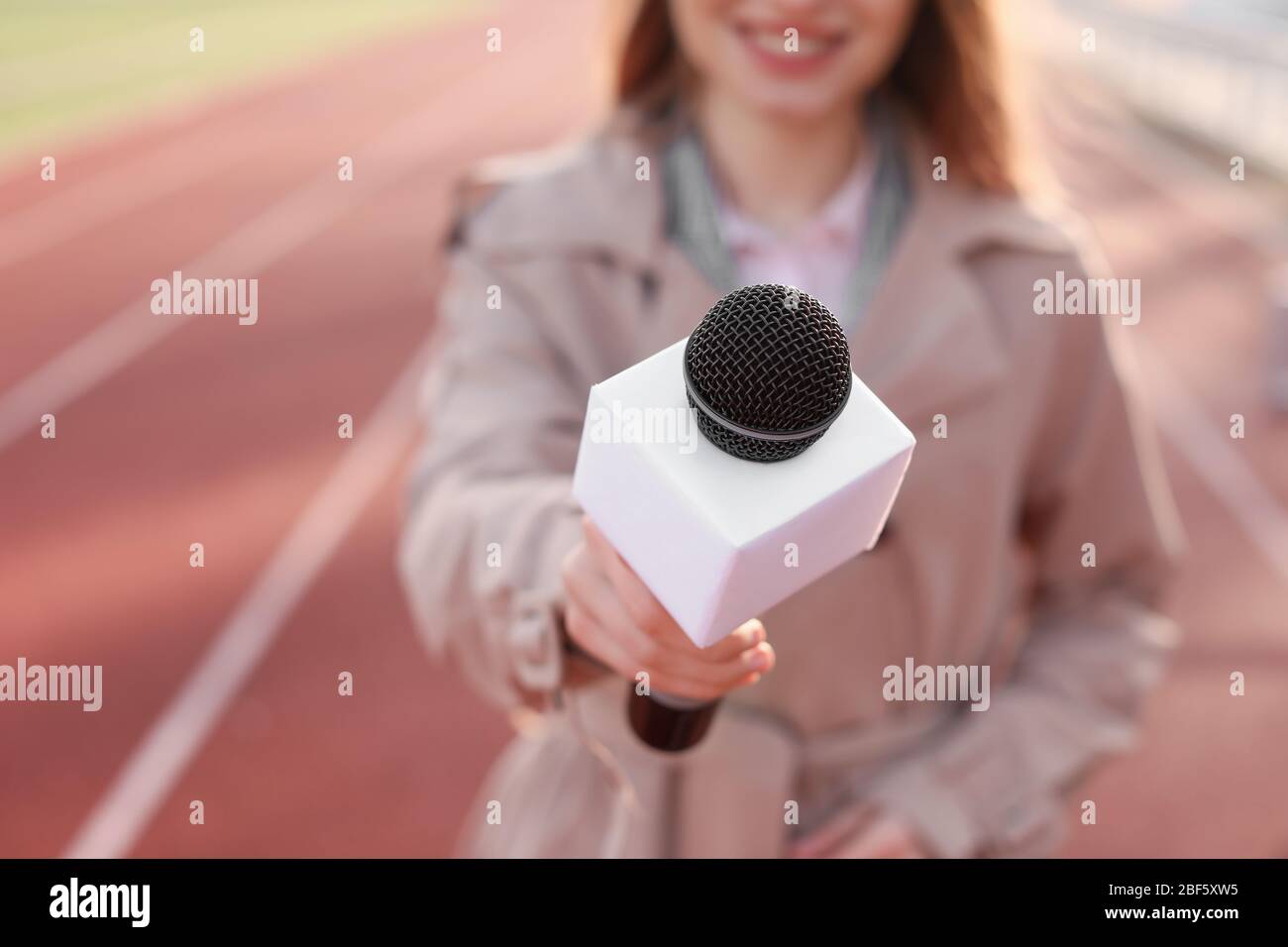 Beautiful reporter with microphone at the stadium, closeup Stock Photo ...