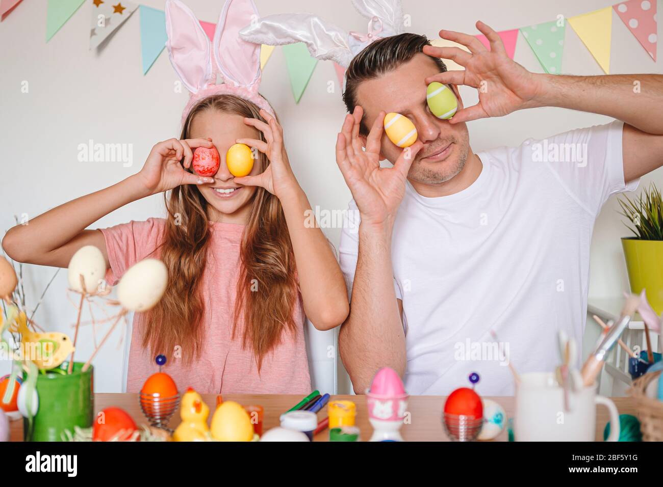 Father and his little daughter painting eggs. Happy family preparing ...