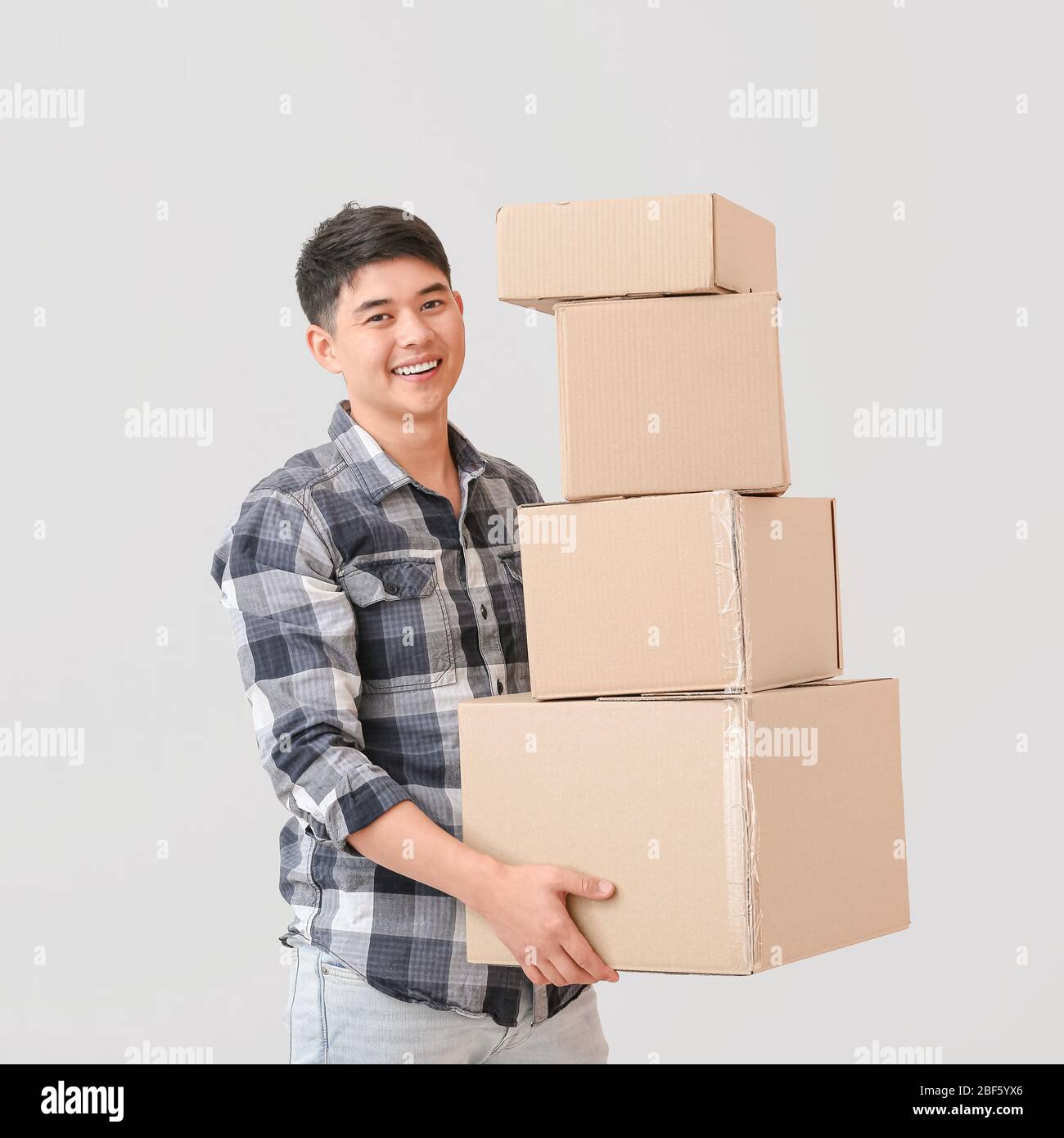 Asian man with moving boxes on light background Stock Photo - Alamy