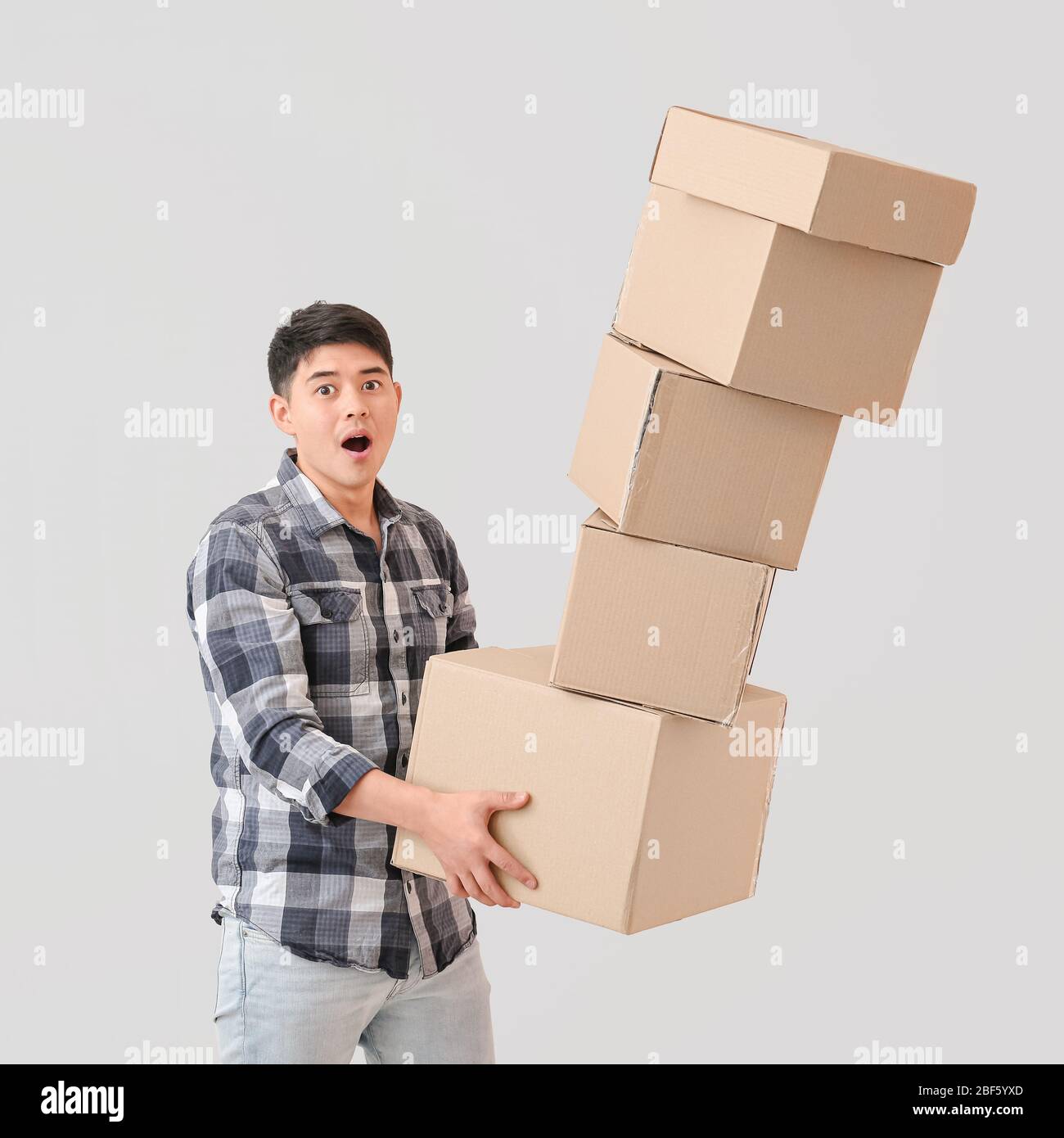 Asian man dropping moving boxes on light background Stock Photo - Alamy